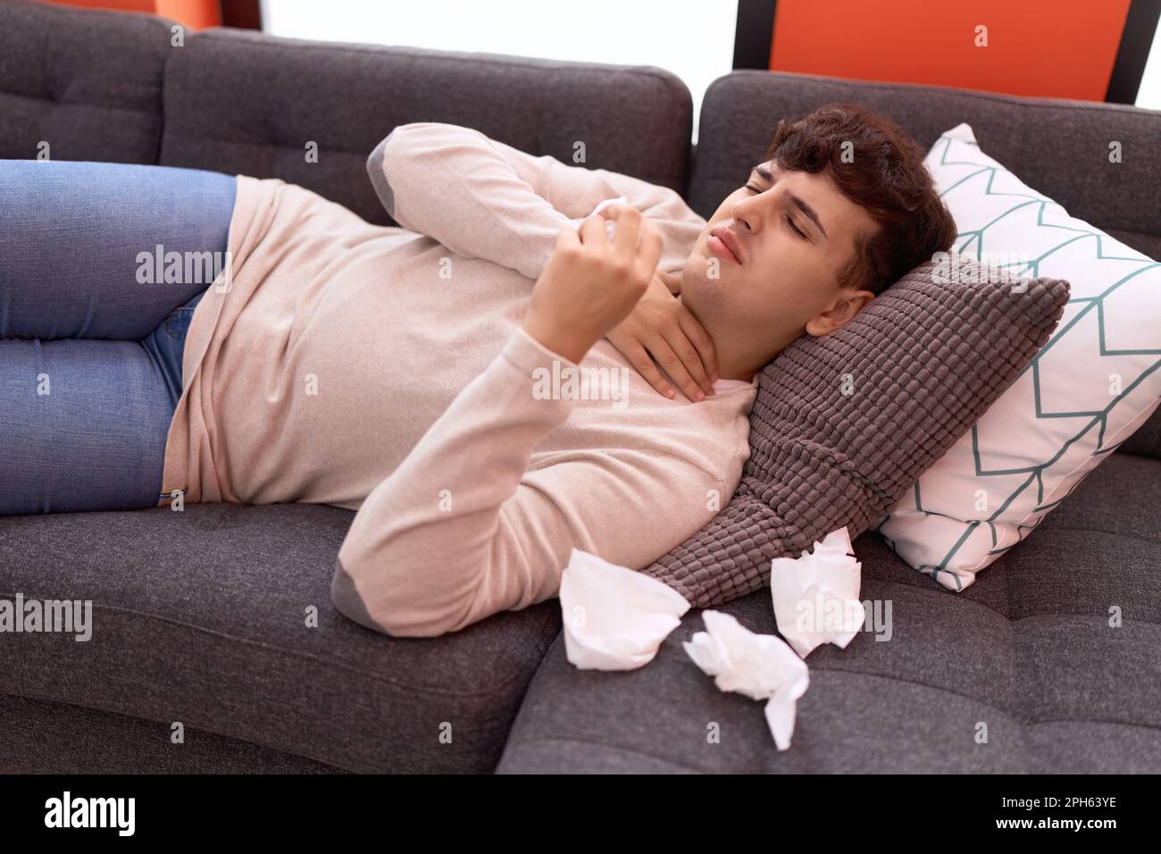 Non binary man lying on sofa using napkin at home Stock Photo - Alamy