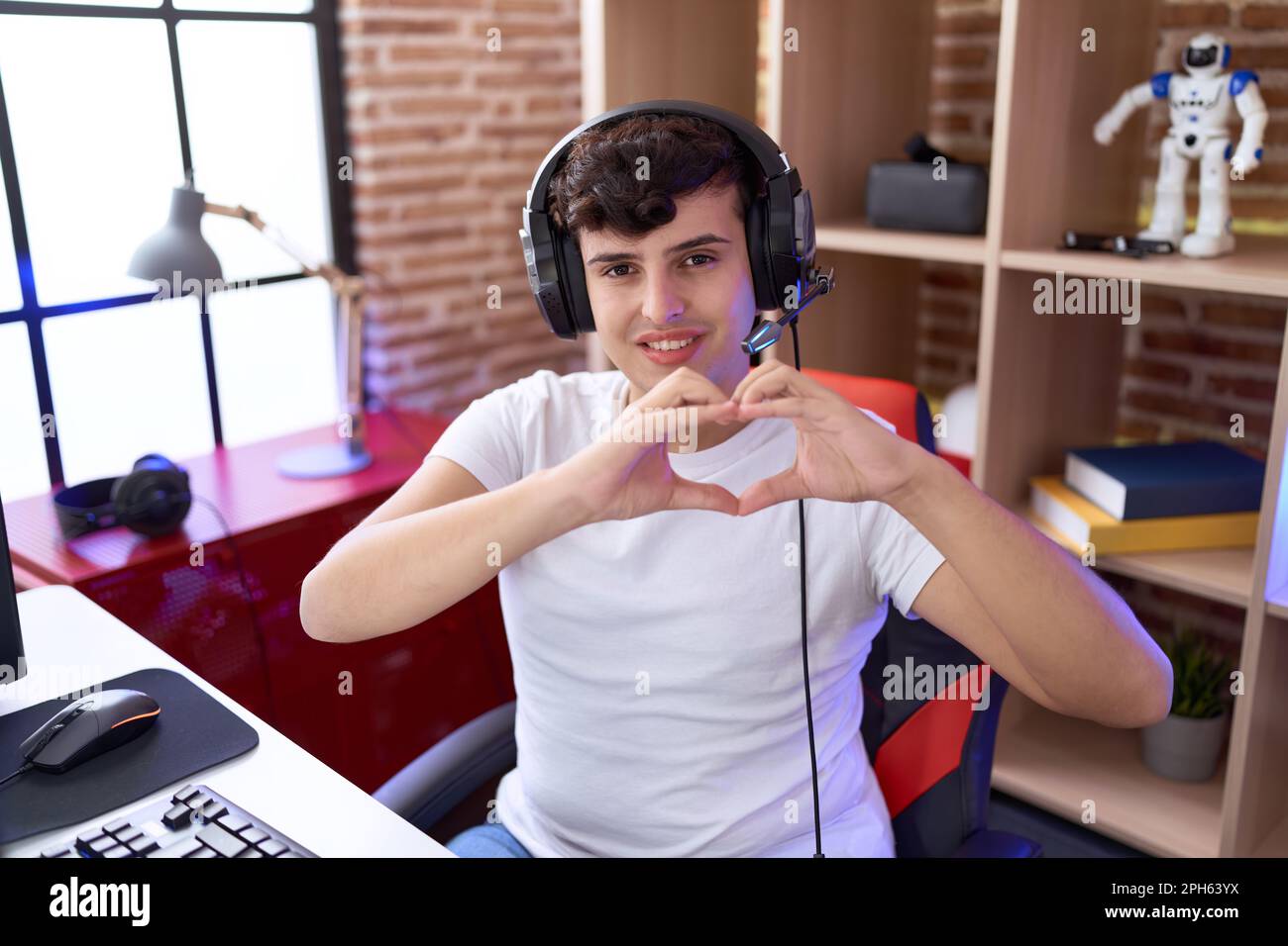 Non binary man streamer smiling confident doing heart symbol with hands ...