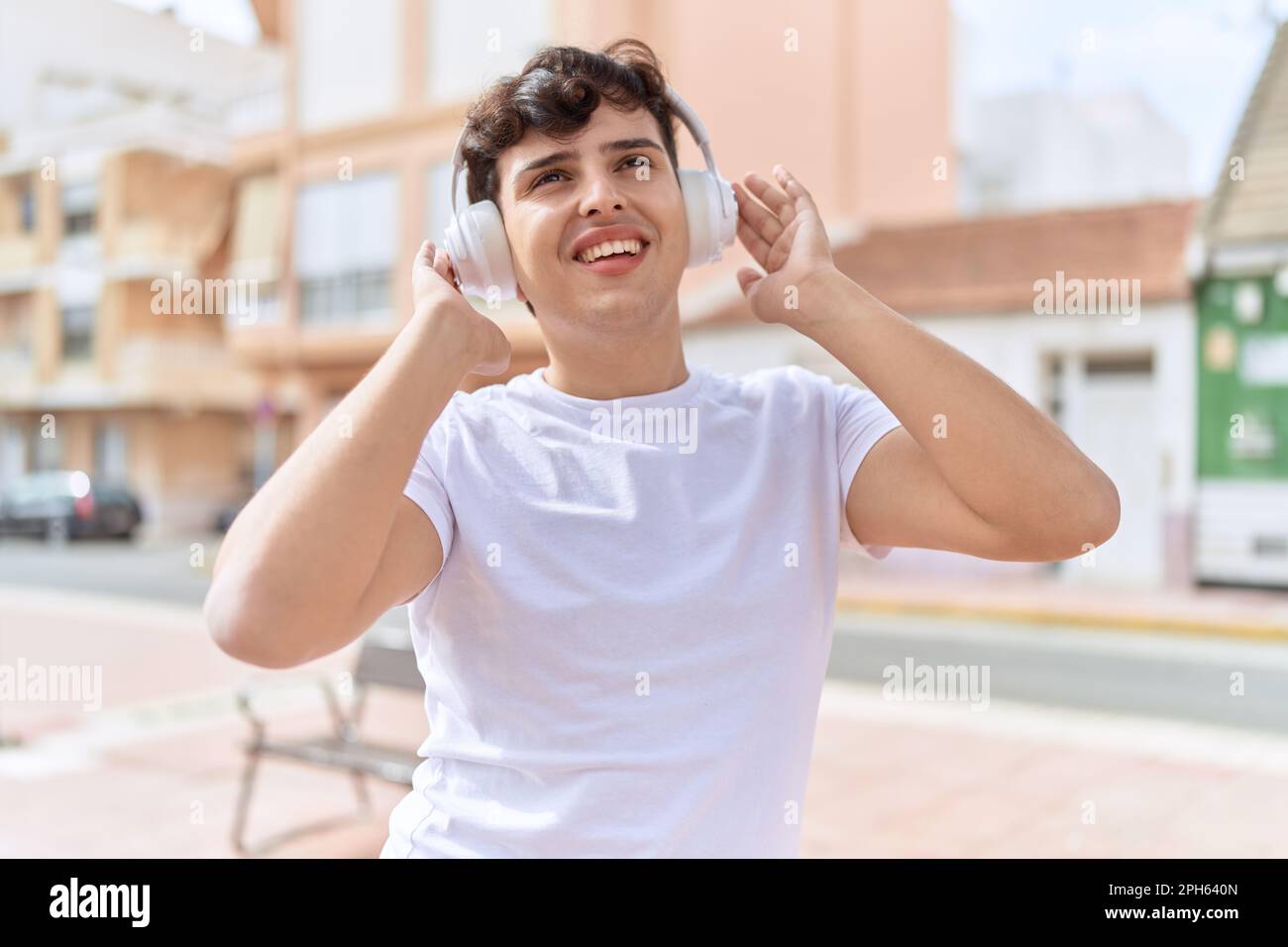 Non binary man listening to music standing at street Stock Photo - Alamy