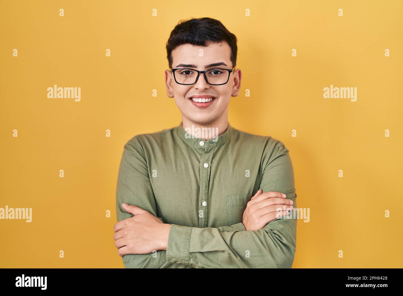 Non binary person standing over yellow background happy face smiling ...