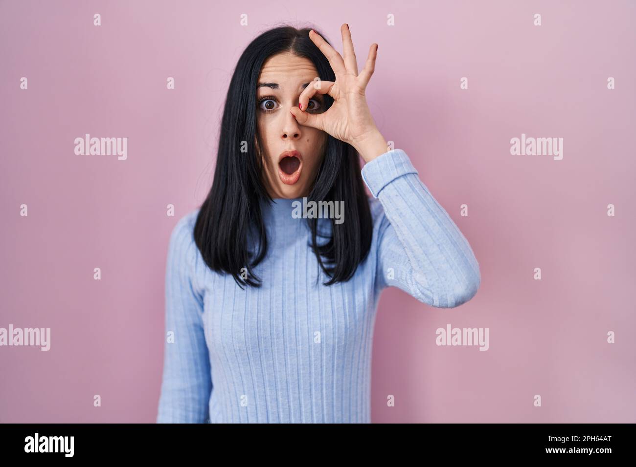 Hispanic woman standing over pink background doing ok gesture shocked ...