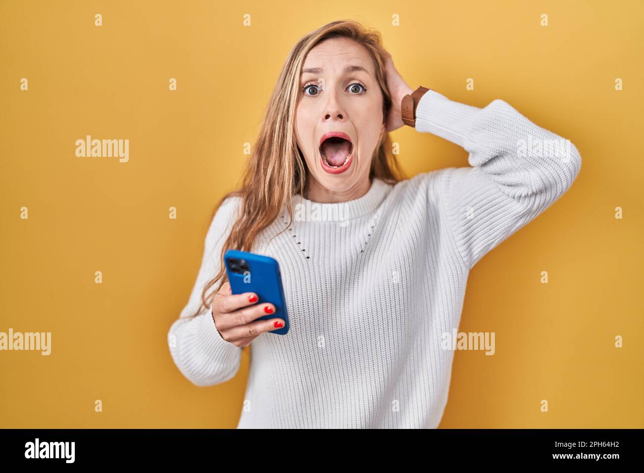 Young blonde woman using smartphone typing message crazy and scared ...