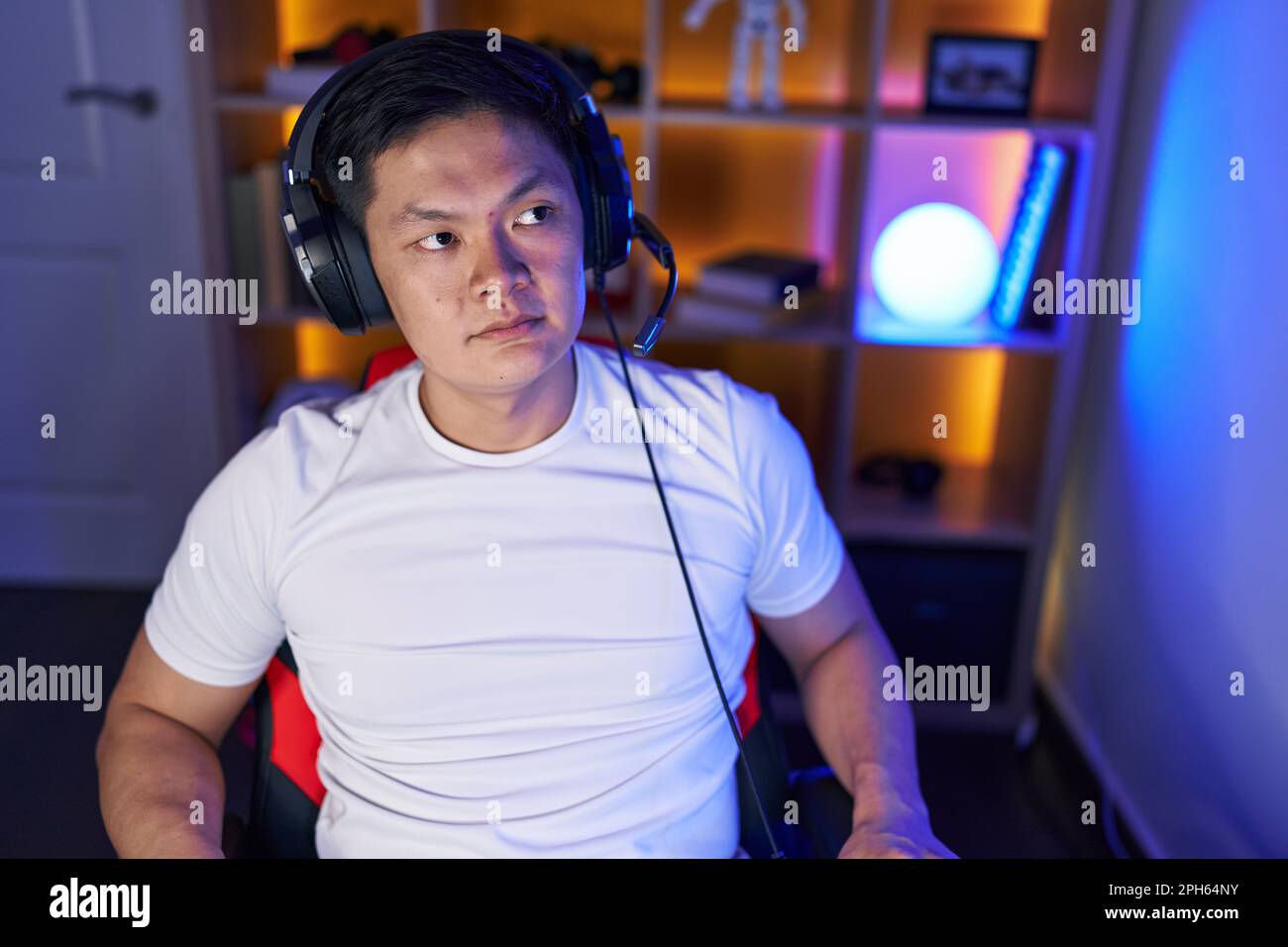 Young chinese man streamer sitting on table with serious expression at ...
