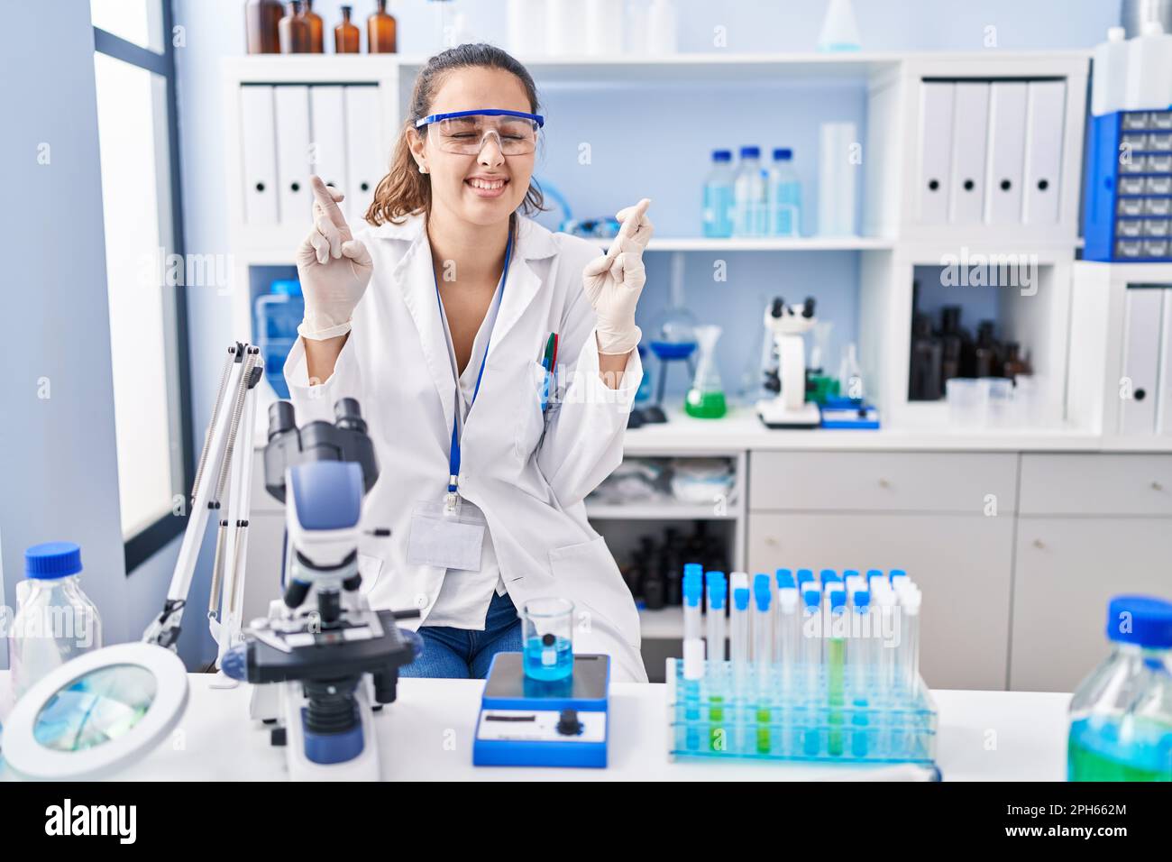 Young hispanic woman working at scientist laboratory gesturing finger ...