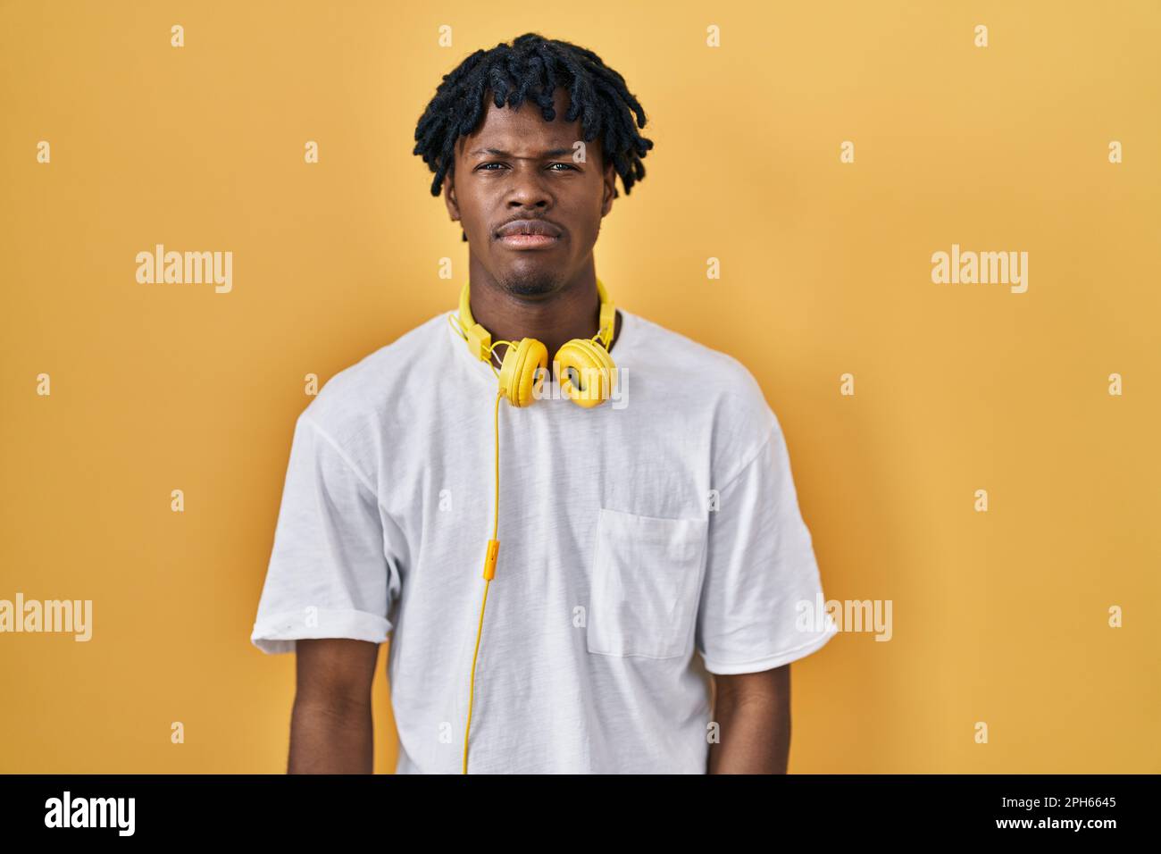 Young african man with dreadlocks standing over yellow background ...