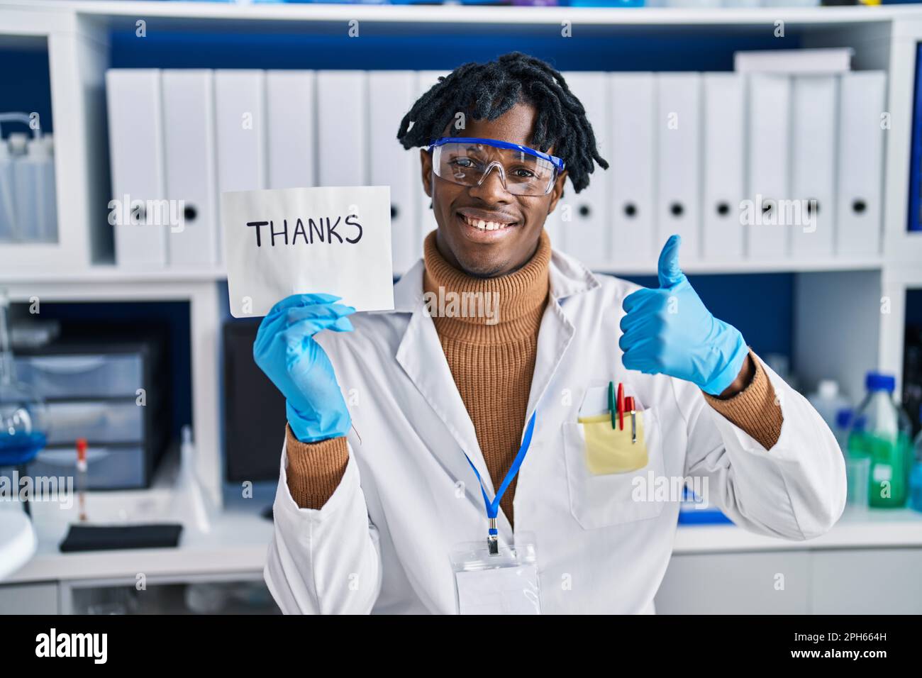 Young african man with dreadlocks working at scientist laboratory smiling happy and positive ...