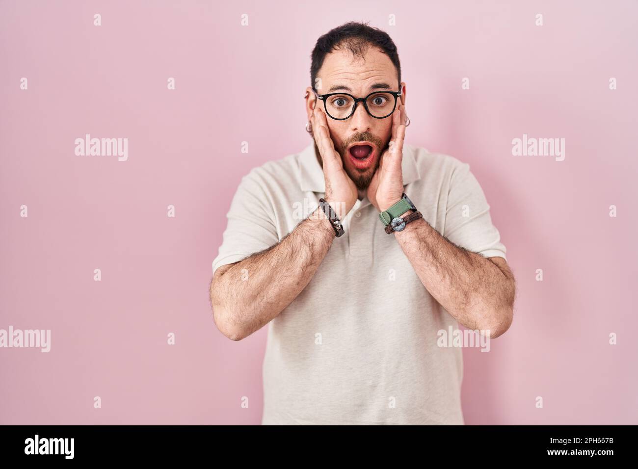 Plus size hispanic man with beard standing over pink background afraid ...