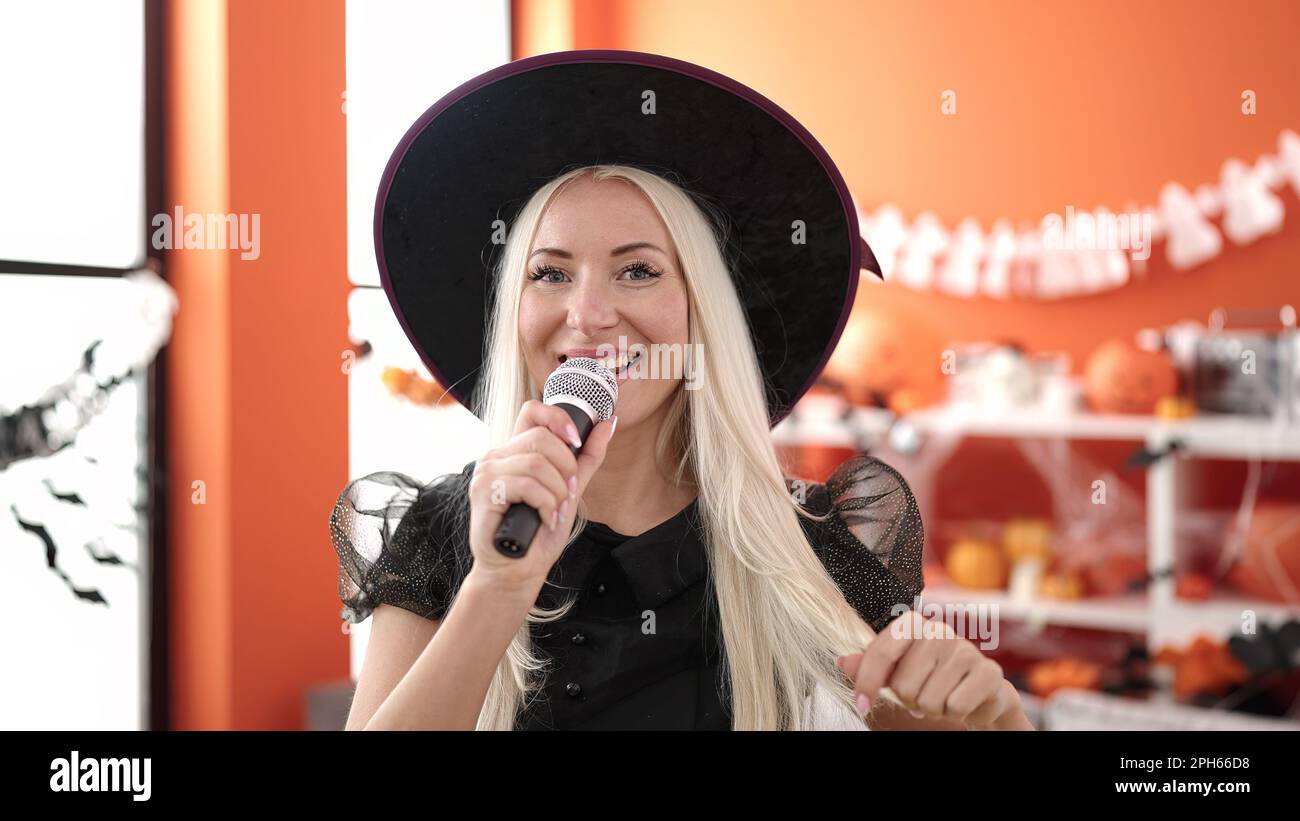 Young blonde woman wearing witch costume singing song at home Stock ...