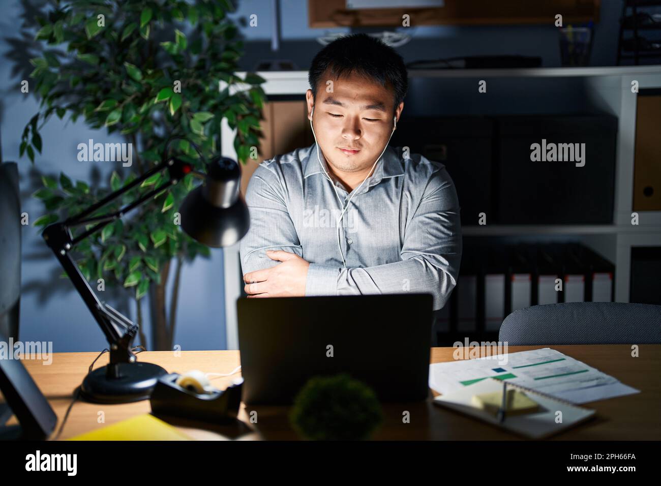 Young chinese man working using computer laptop at night smiling ...