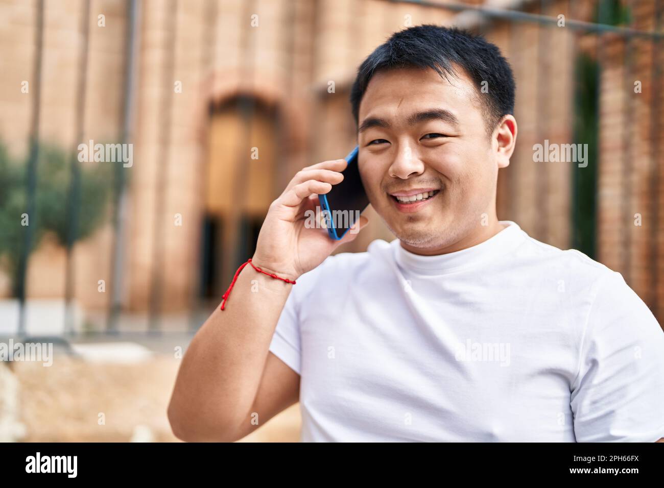 Young chinese man smiling confident talking on the smartphone at street ...