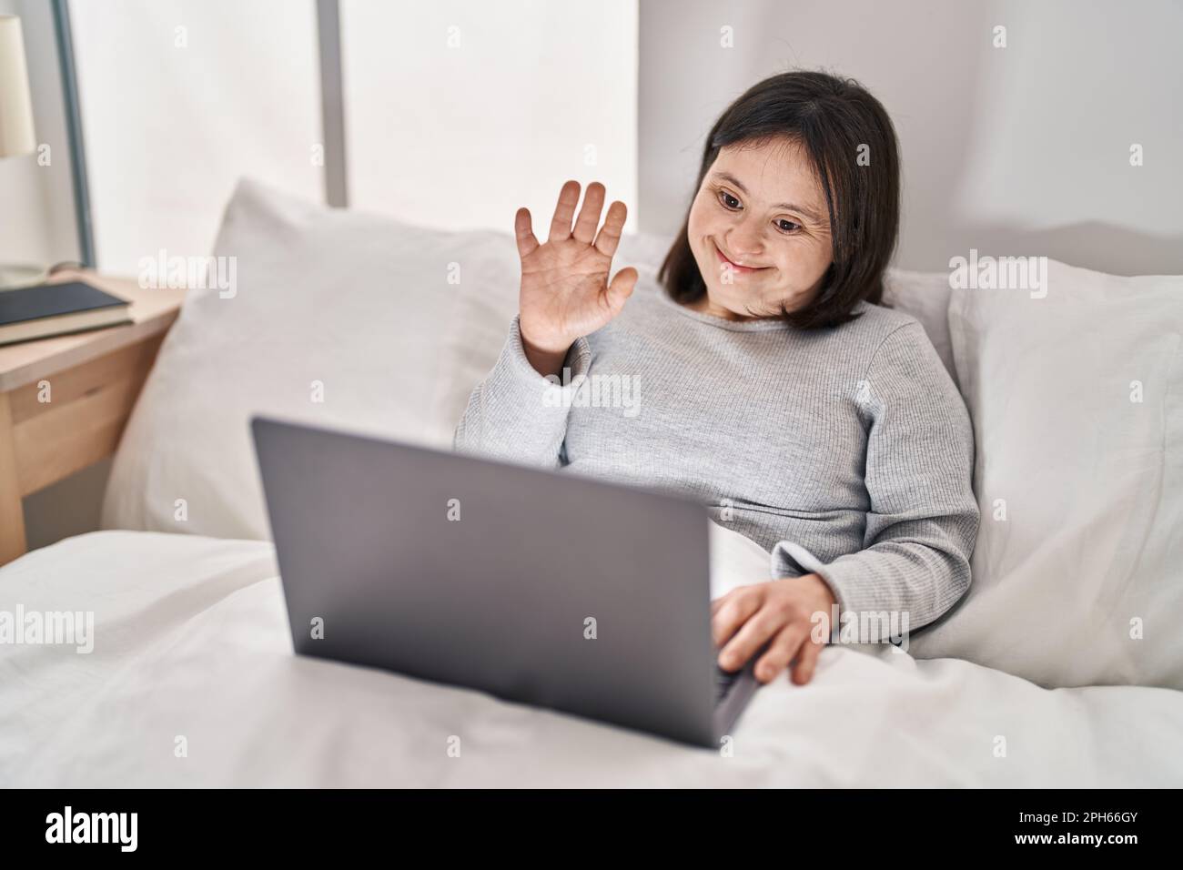 Young woman with down syndrome having video call sitting on bed at ...
