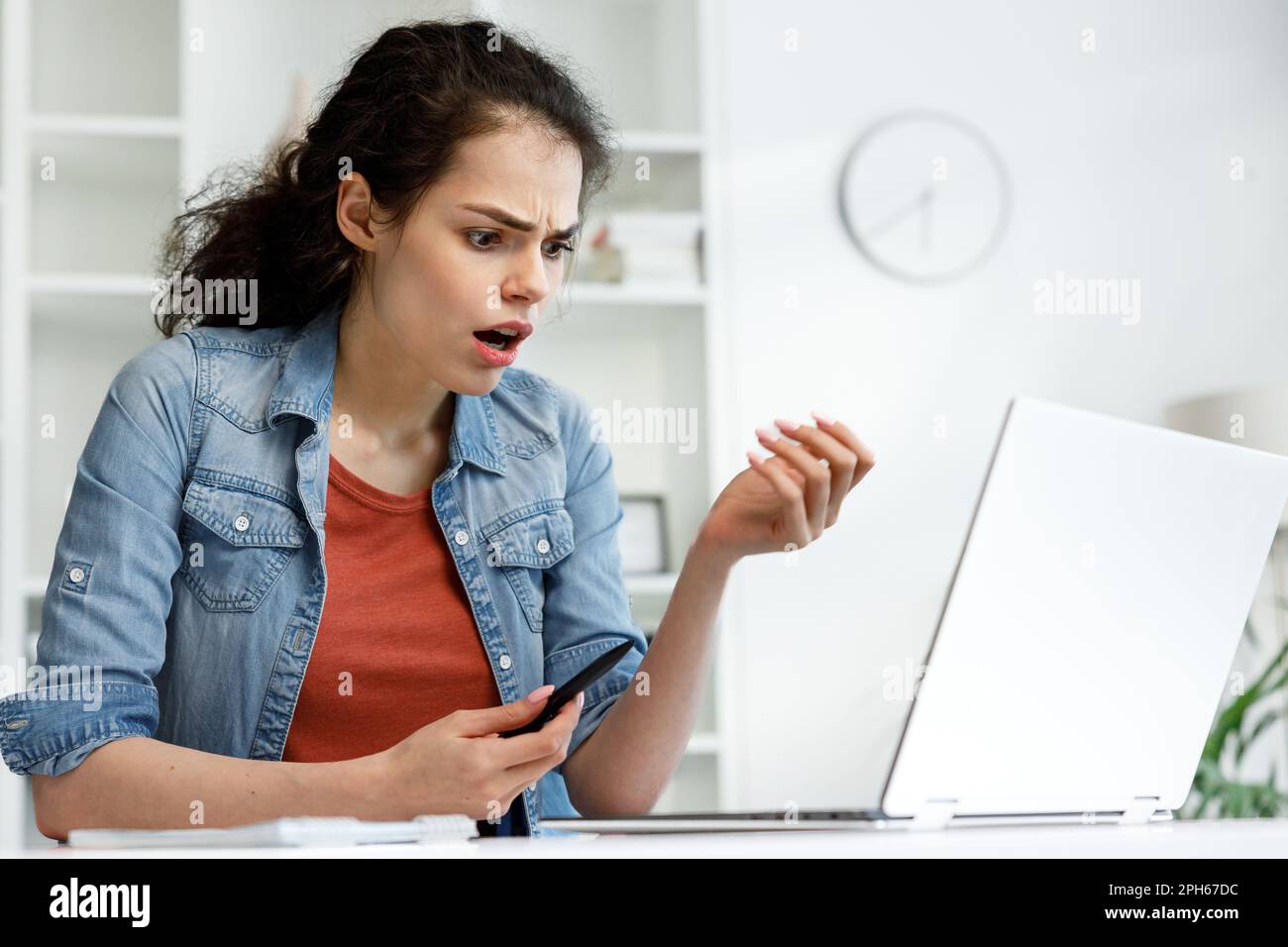 Disappointed girl looks at the laptop screen, does not understand what ...