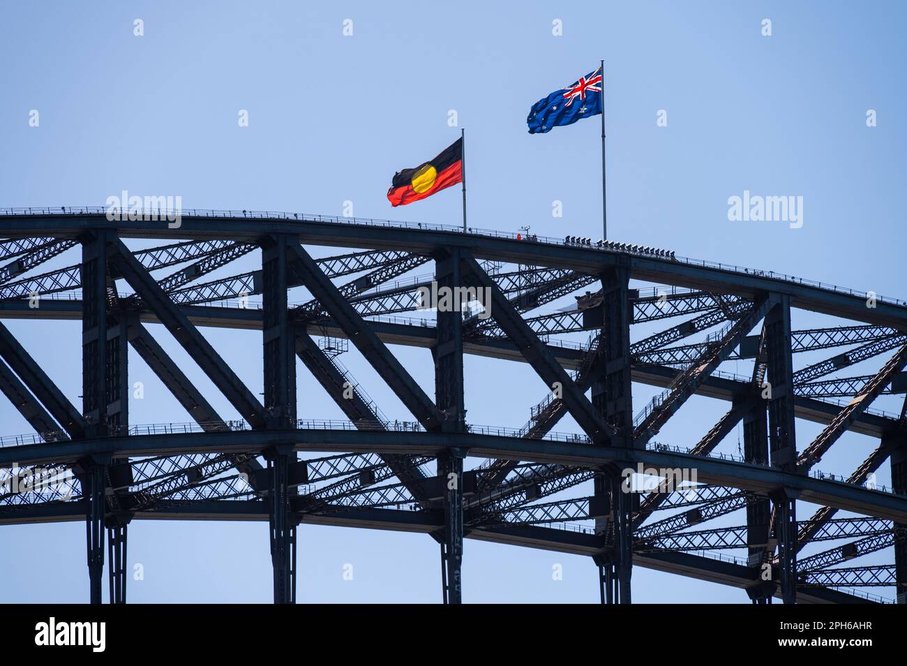 Against a blue sky the Aboriginal flag flies alongside the Australian ...