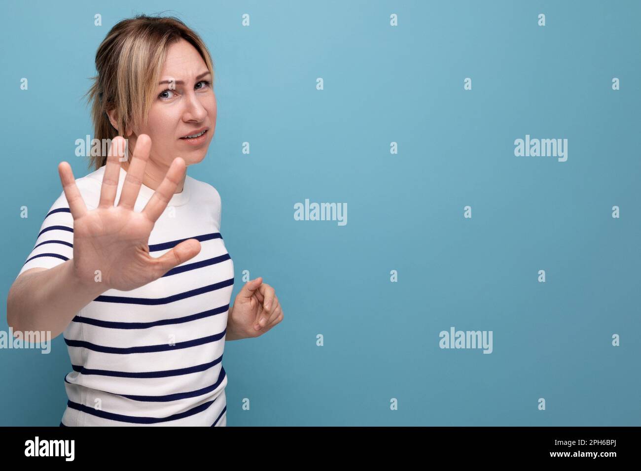 sad blonde girl waving her hand on a blue background with copy space ...