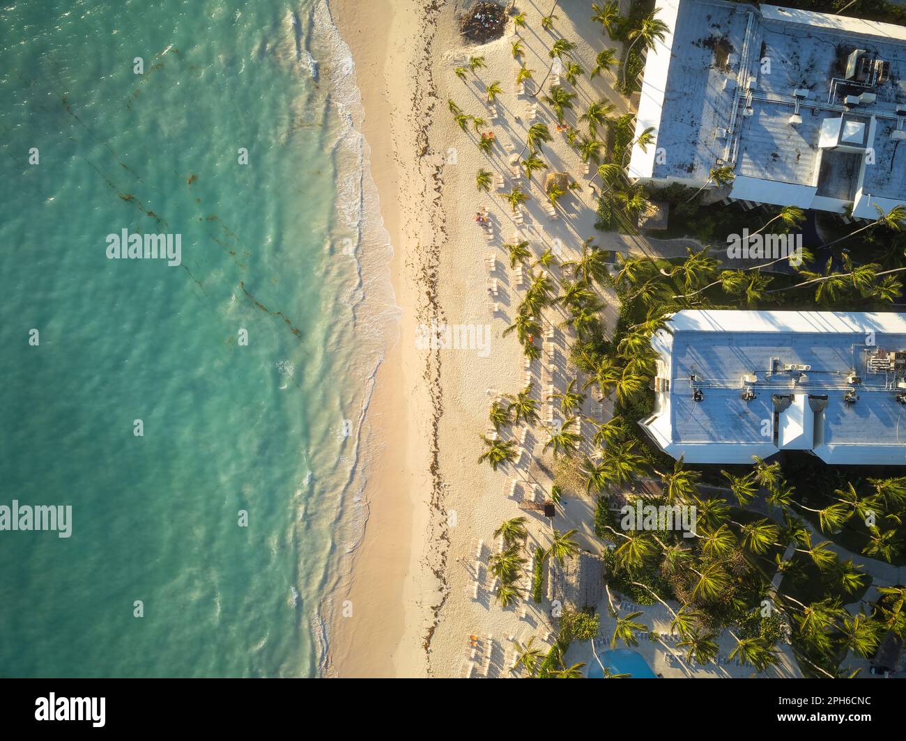 Aerial view of a tropical beach. On the sandy shore roofs of houses ...