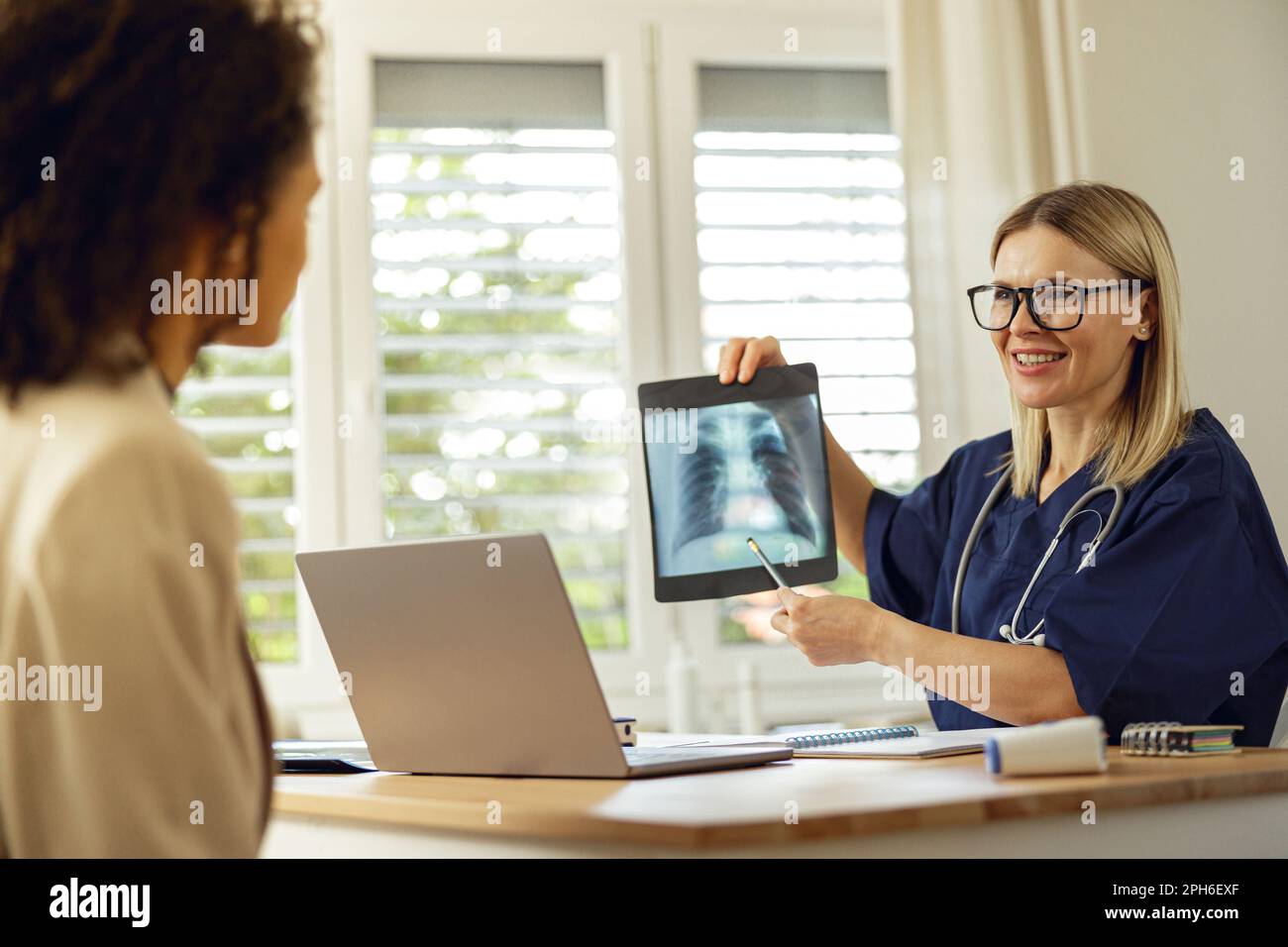 Smiling female doctor showing x-ray to patient at medical office in ...
