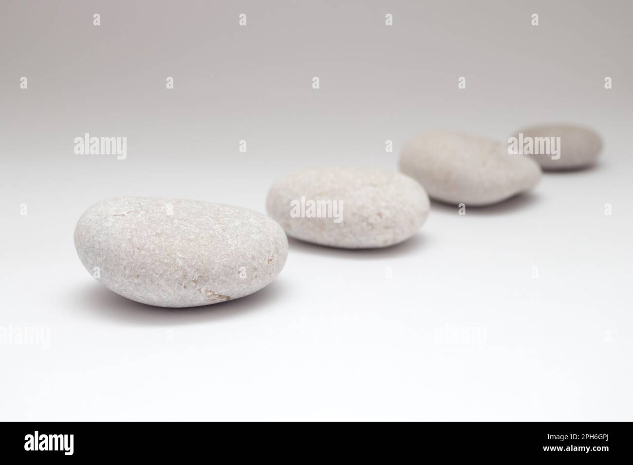a row of smooth pebbles on white background Stock Photo - Alamy
