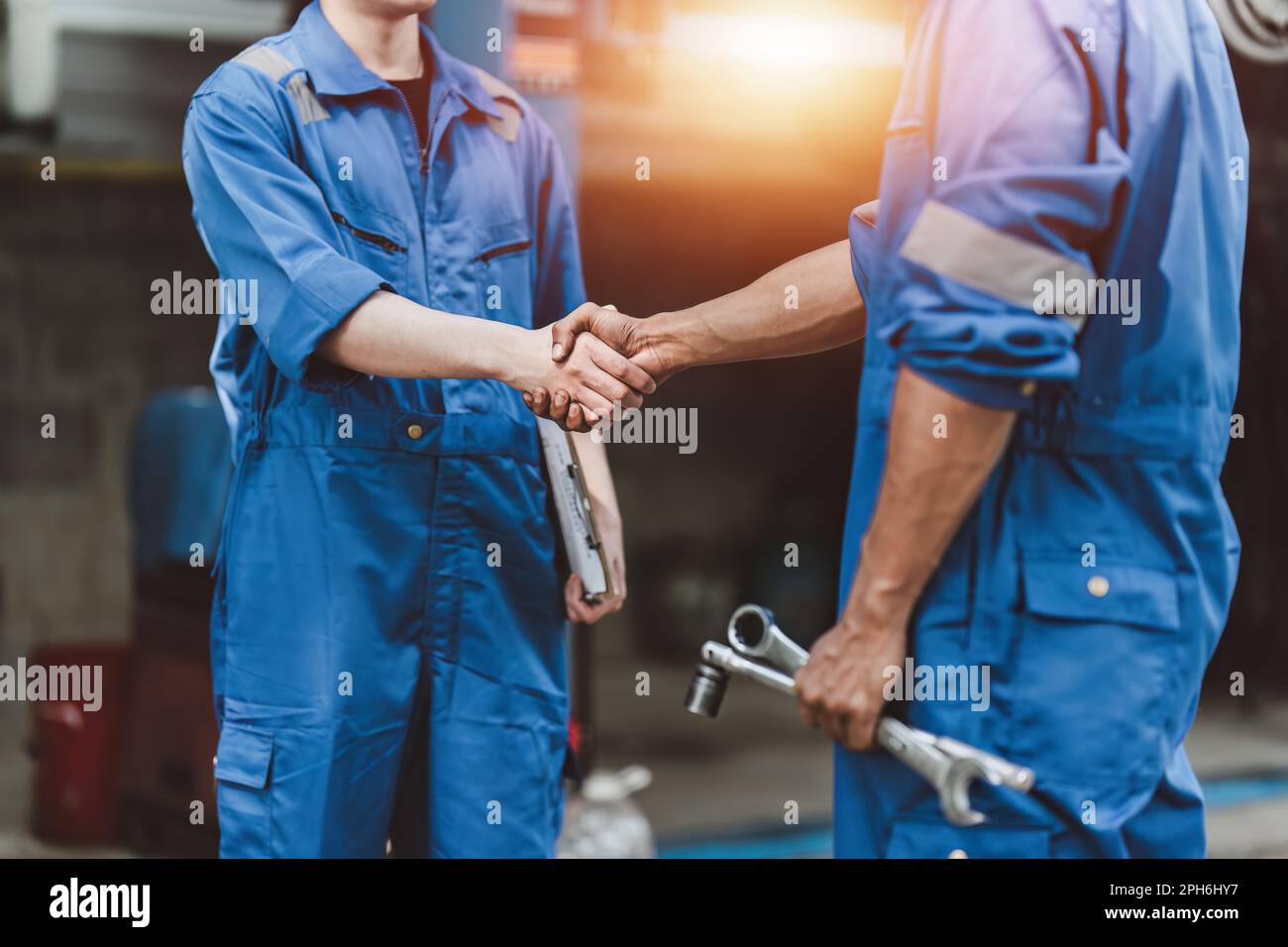 Expert auto mechanic handshake and working together at garage ...