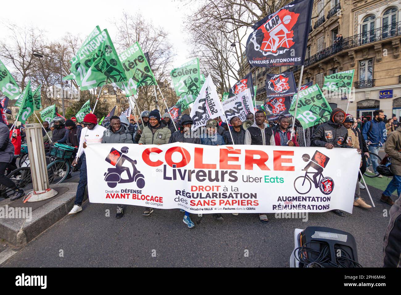 Paris, France. 25th Mar, 2023. Couriers migrants hold a flags and ...