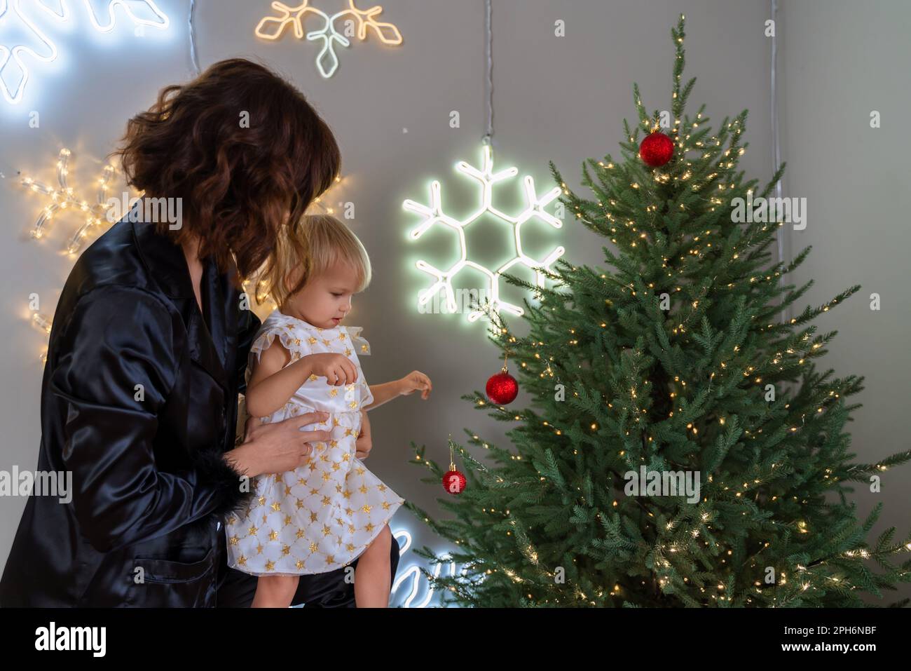 A Mother With A 2 Year Old Daughter Decorates The Christmas Tree Mom