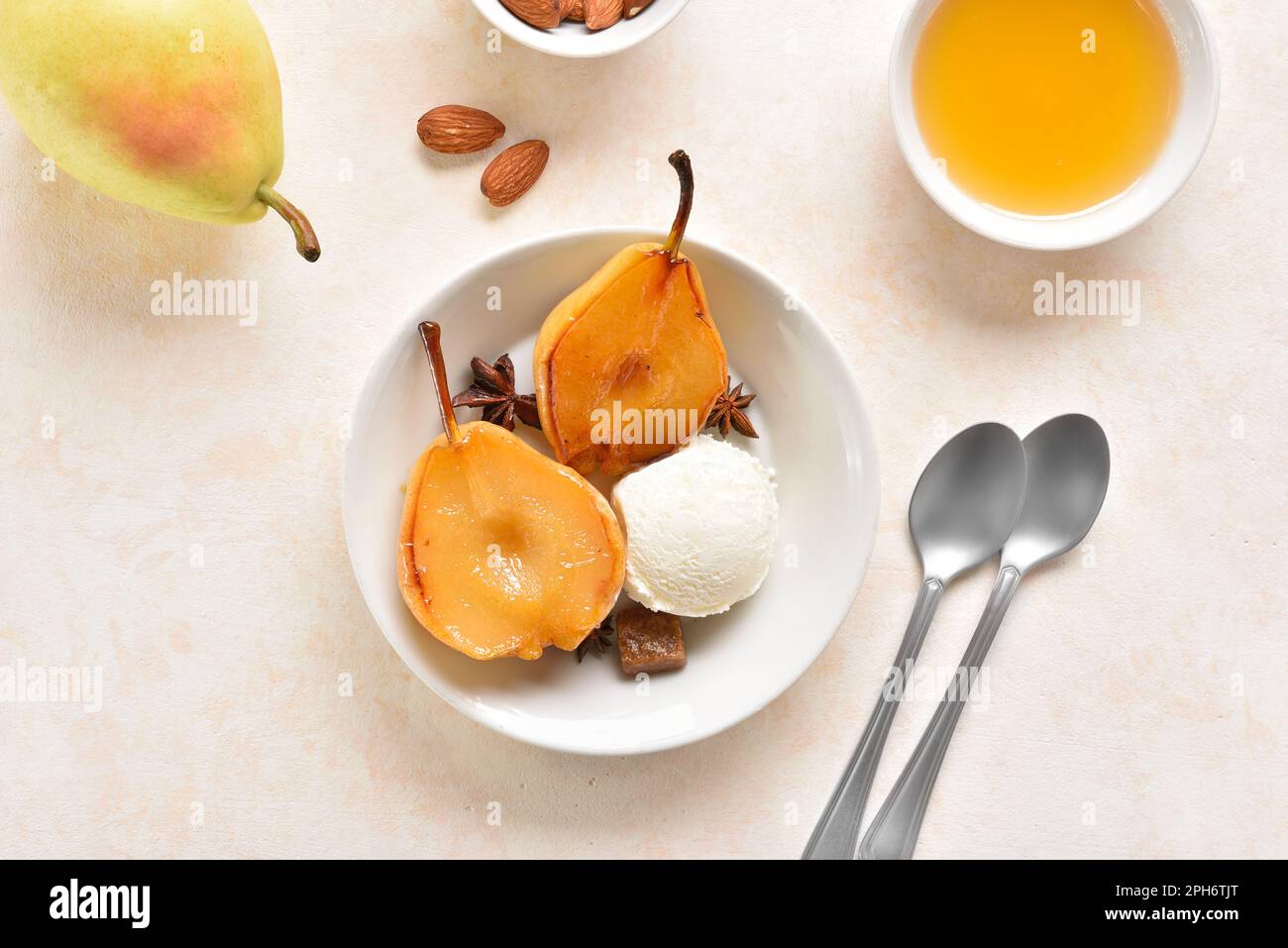 Vanilla poached pears with ice cream in bowl over light stone ...