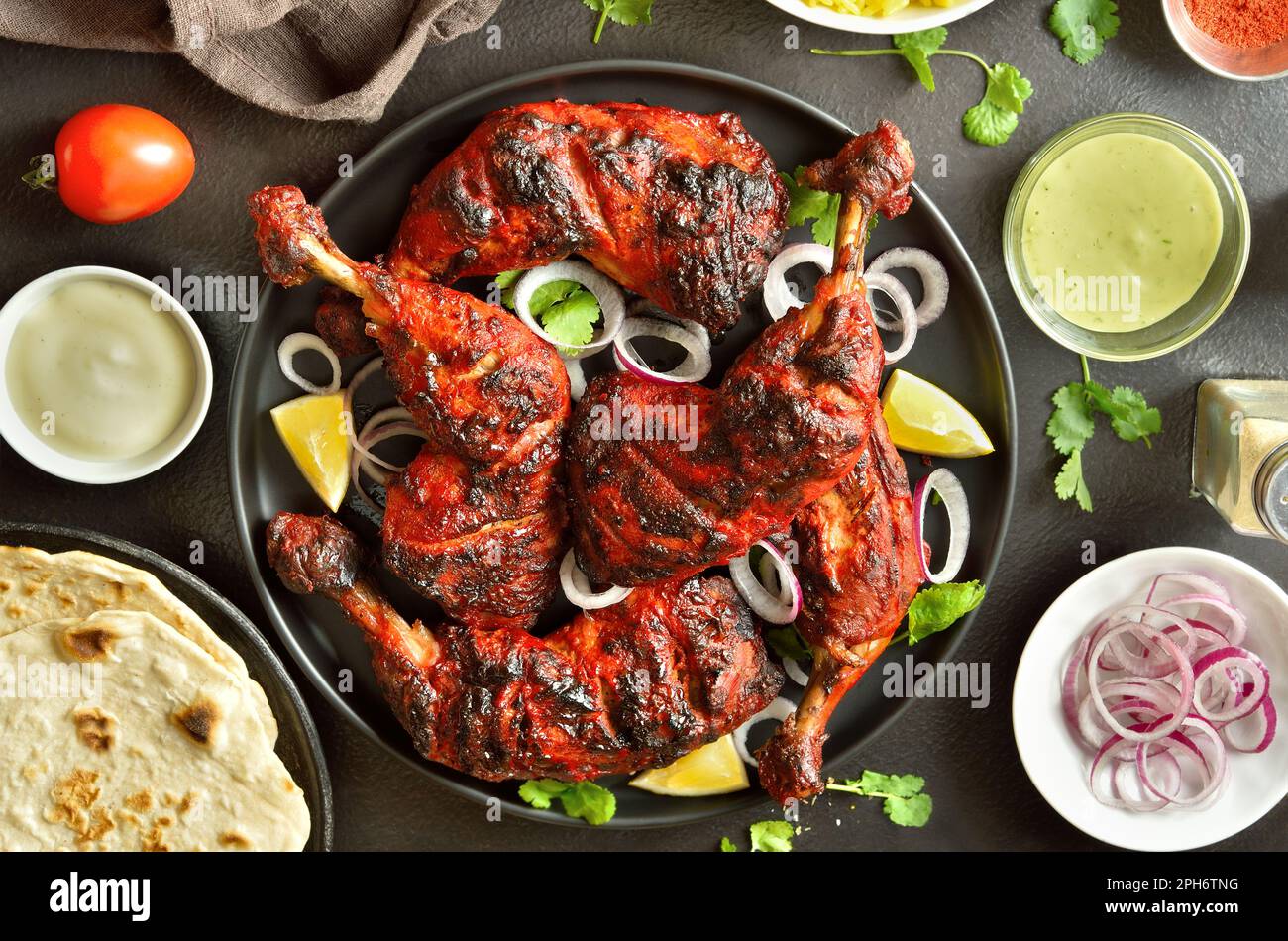 Indian style tandoori chicken on plate over dark stone background ...