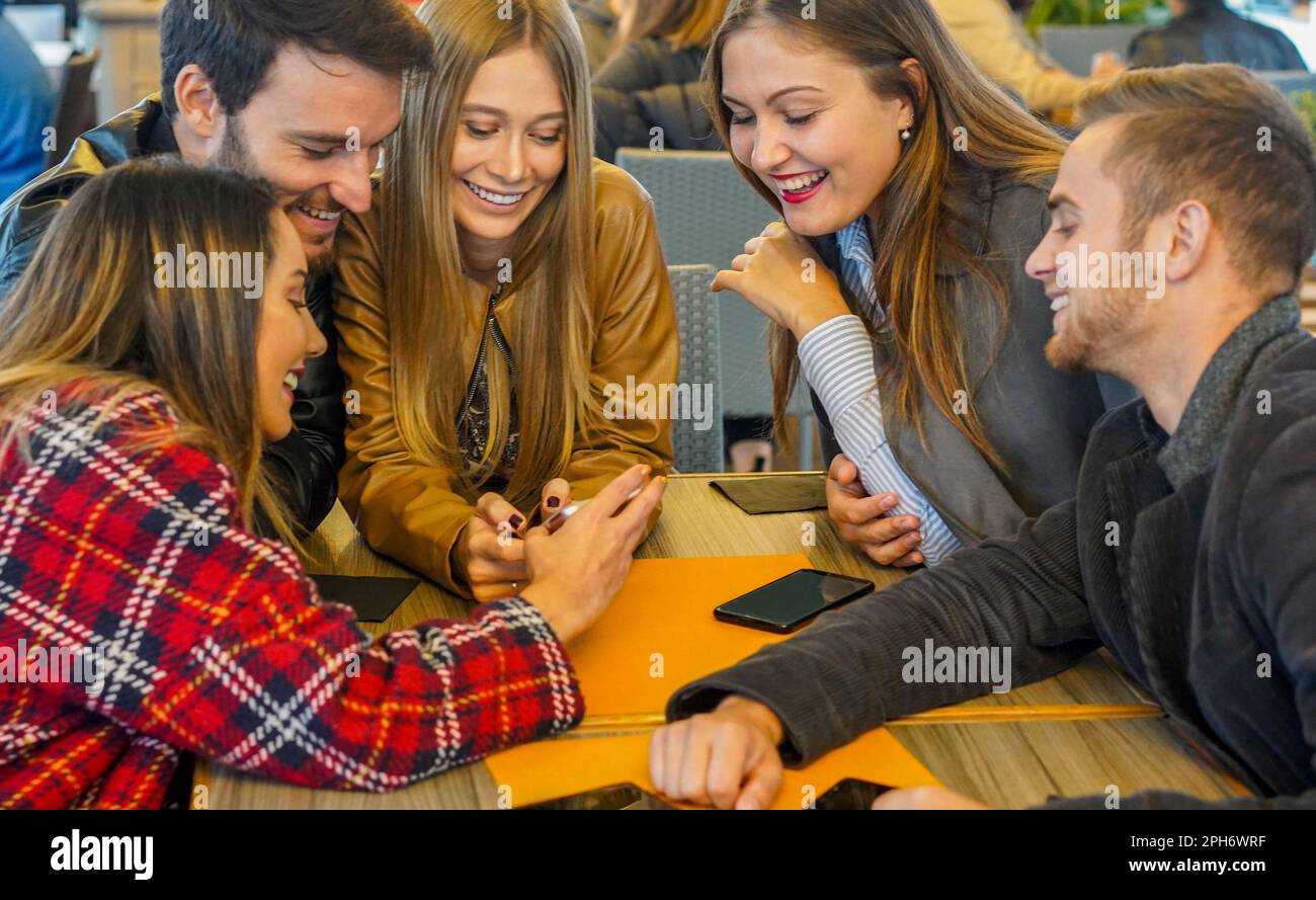 Group of friends hanging out with each other sitting in a bar using ...