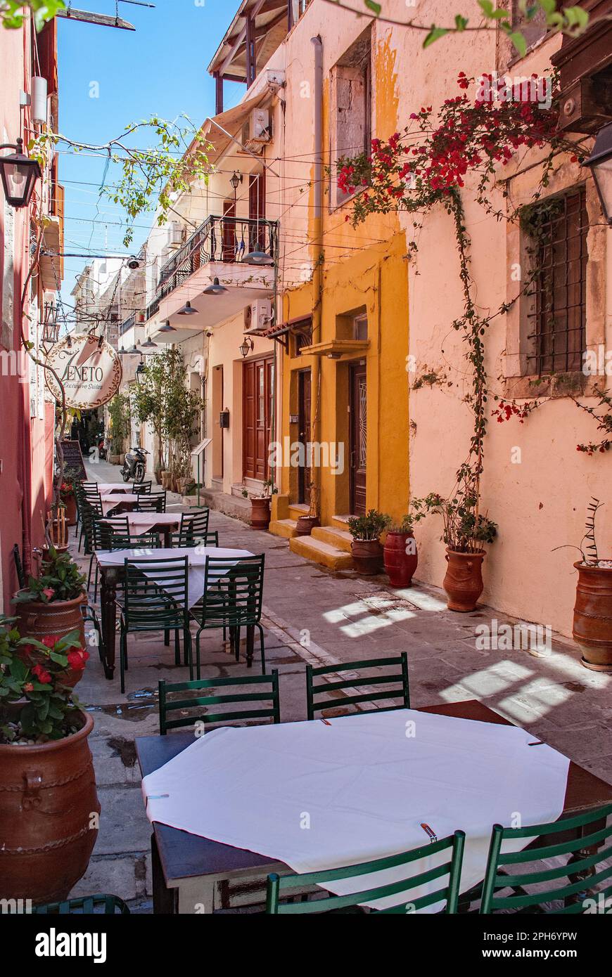 Alleyway lane in Crete with colourful painted restaurant facade and ...