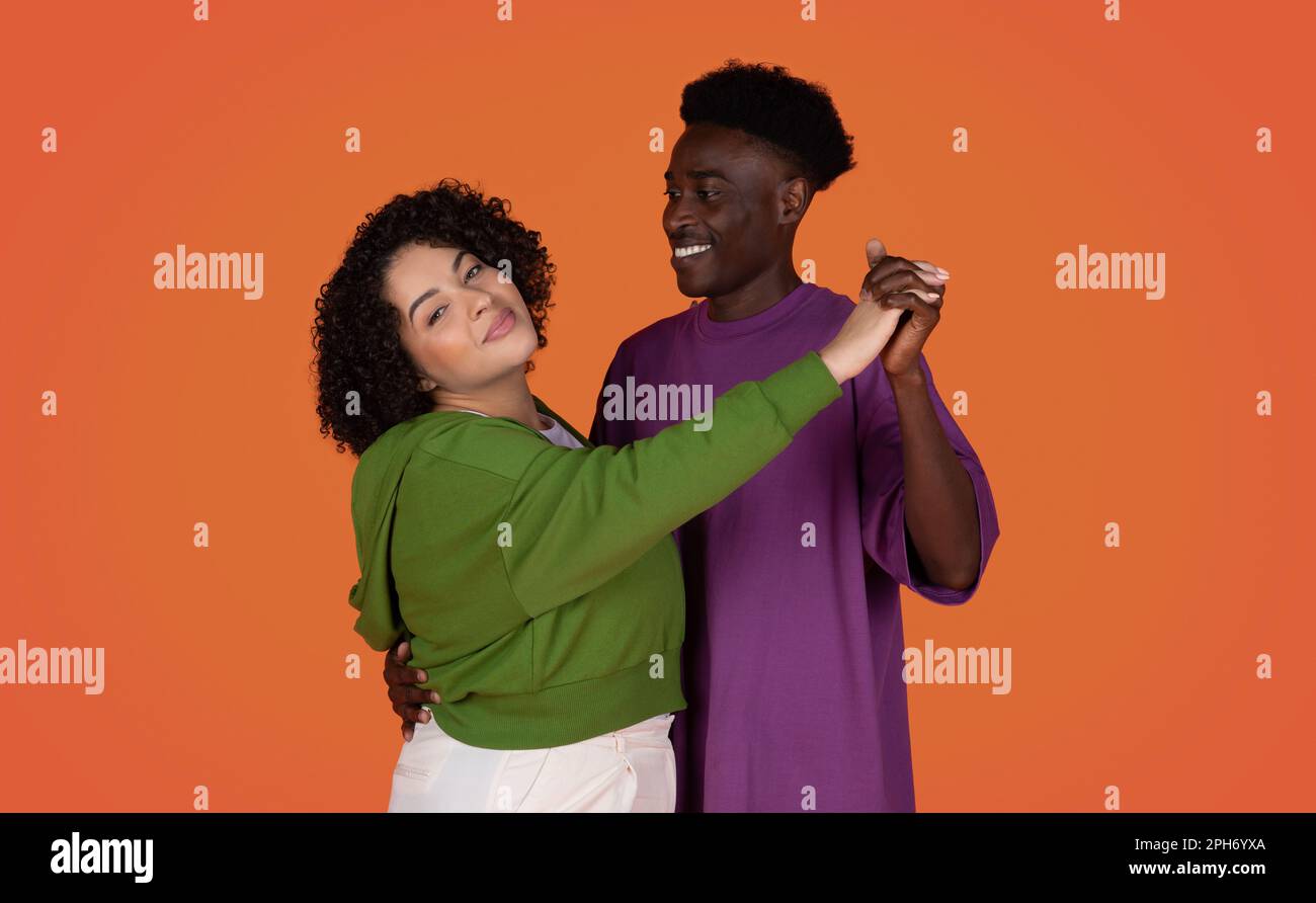 Romantic loving multiracial couple dancing on red studio background ...