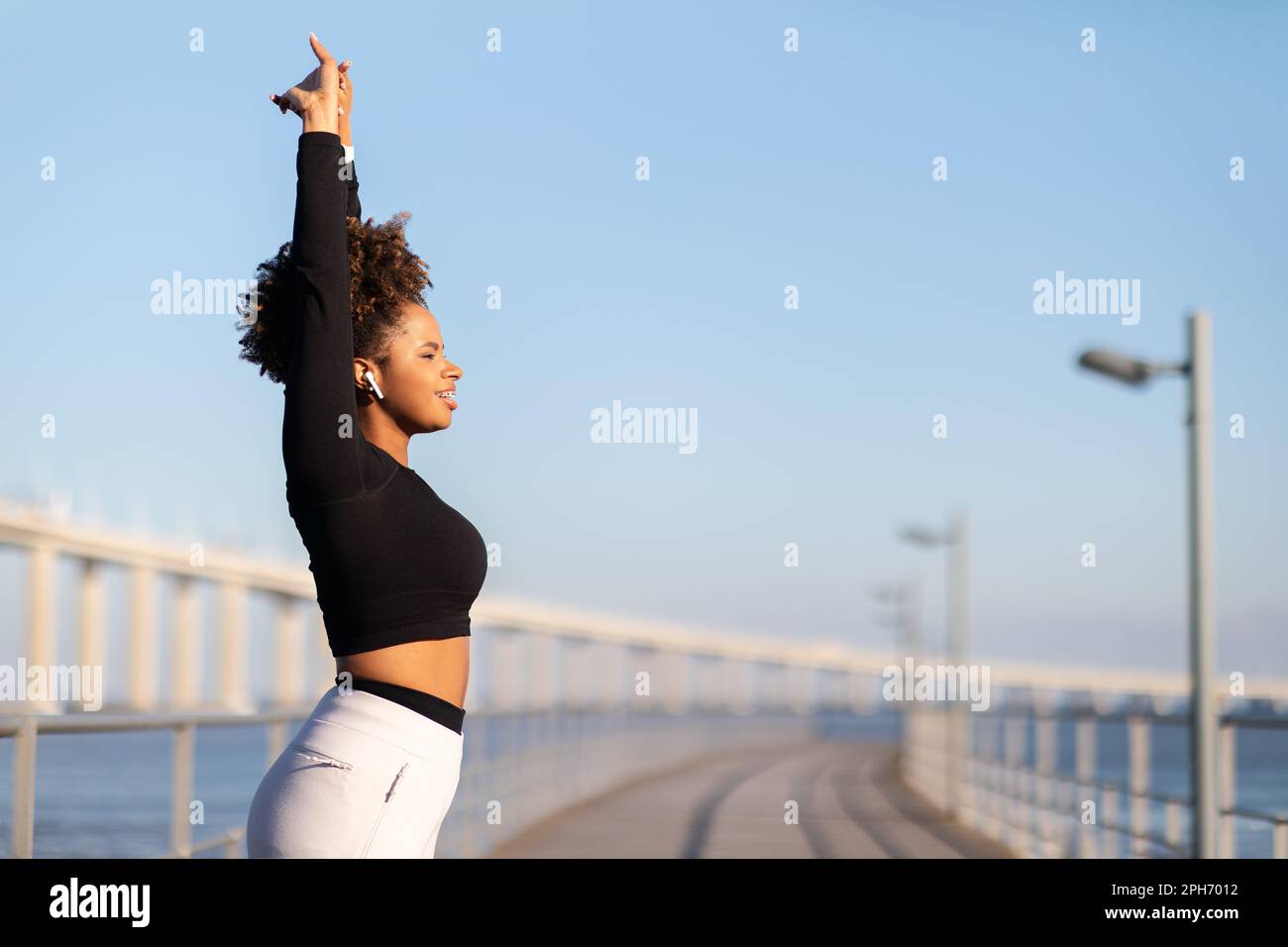 Sporty black woman raising hands, stretching arm muscles while training ...