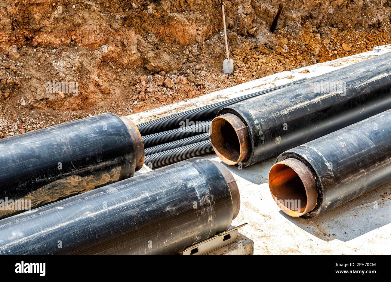 Construction works on large iron pipes at a depth of excavated trench ...