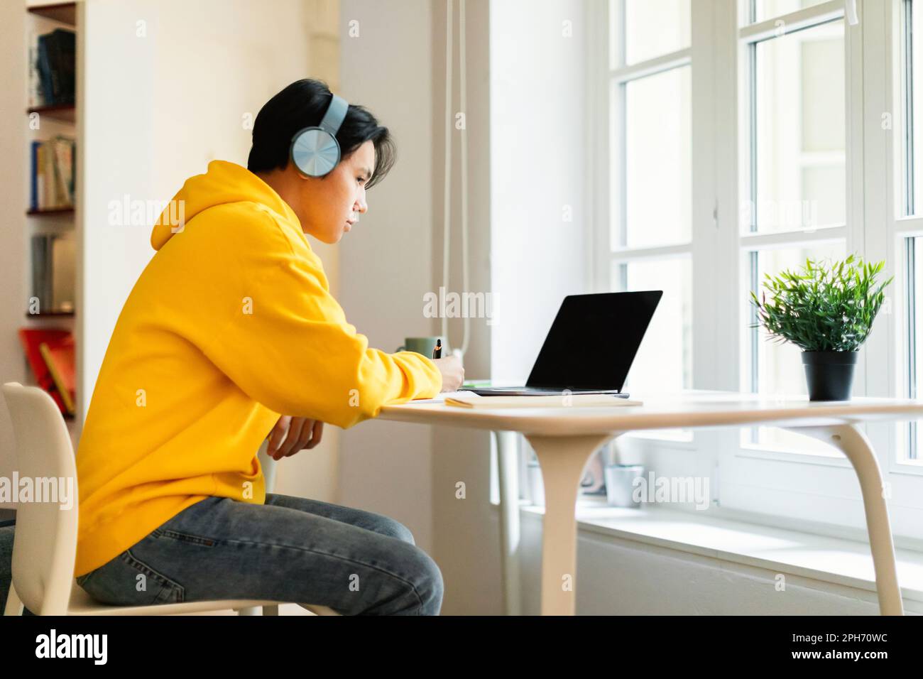 Chinese Teenager Boy Learning At Laptop Wearing Headphones At Home ...