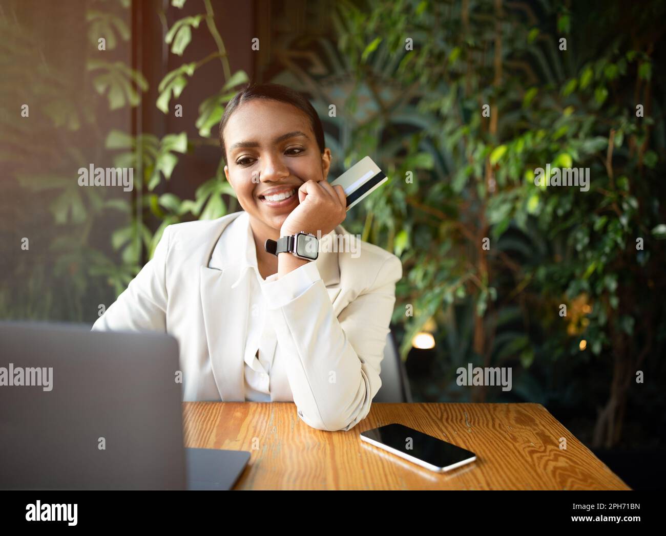 Smiling young black lady in suit typing on laptop, hold credit card to ...