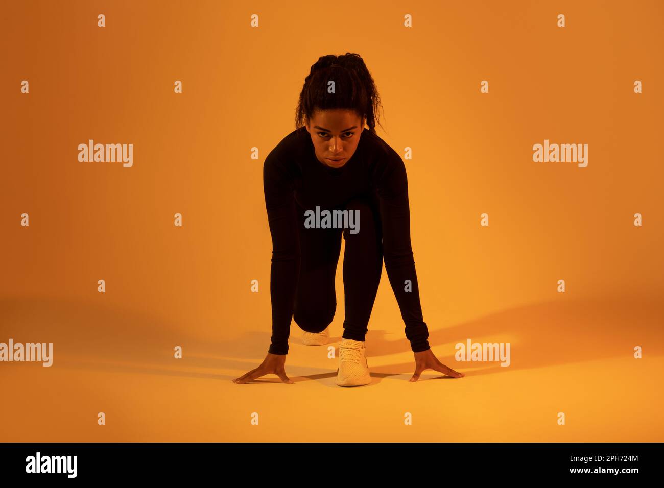 Motivated african american female runner doing crouch start, looking at ...