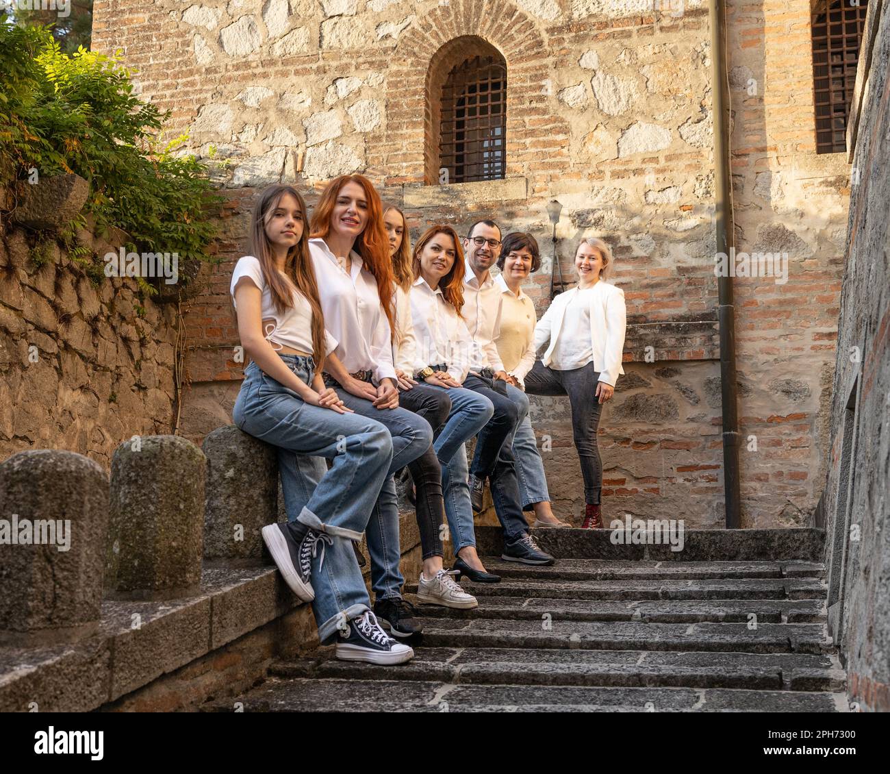 A company of 7 people poses in the morning light on the old steps ...