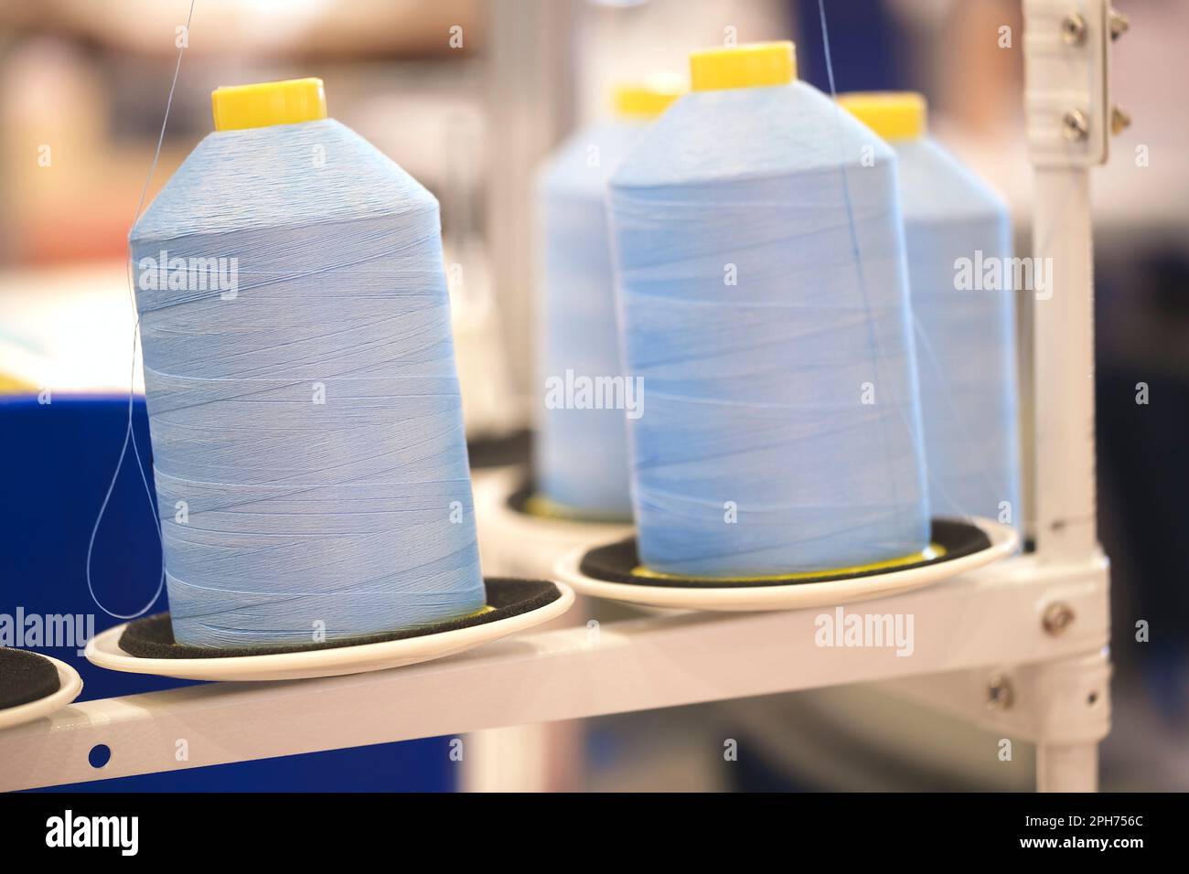 Reels of textile yarn blue thread at industrial weaving manufacturing ...