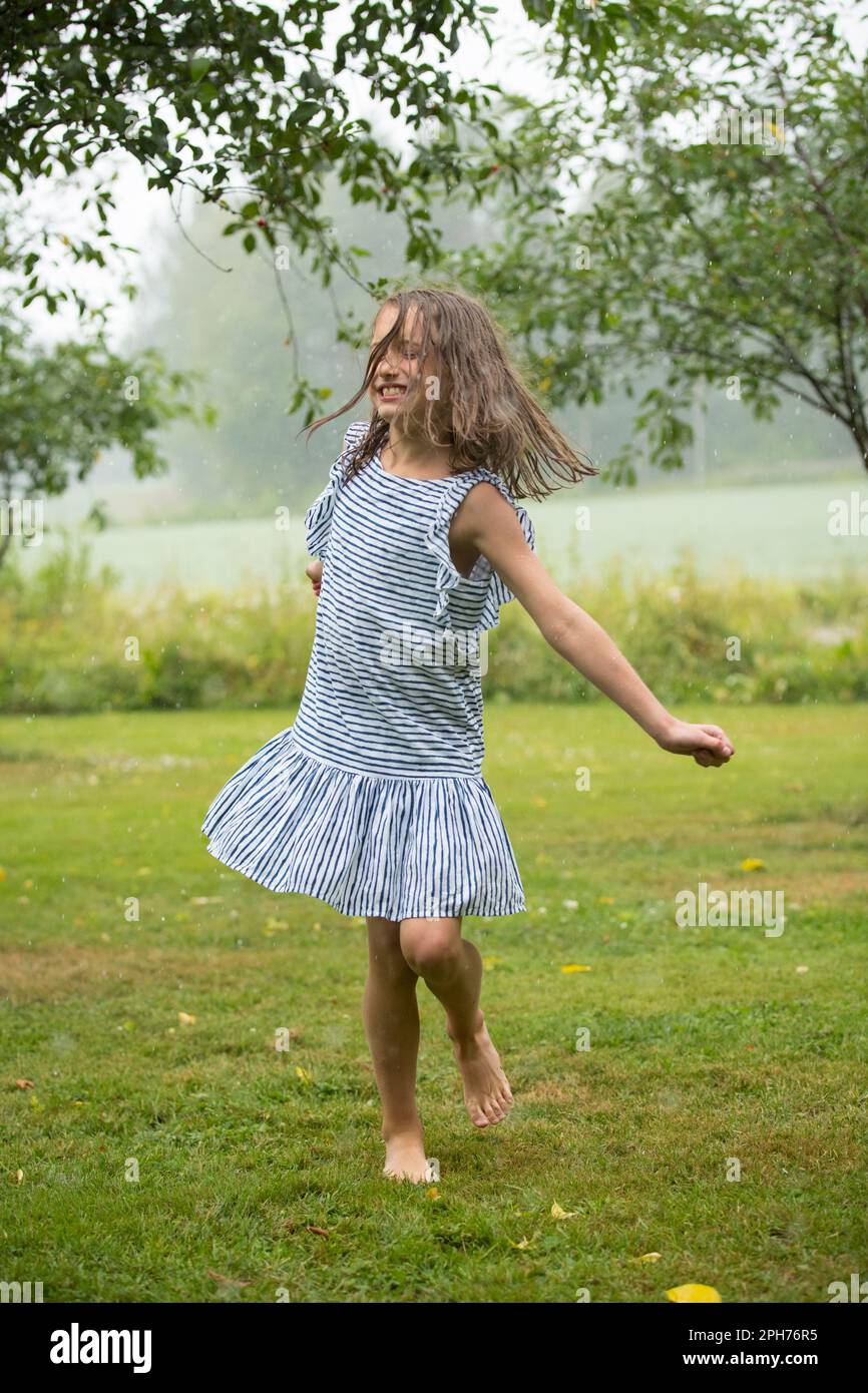 Happy cute little girl in sundress dancing and running on green lawn ...