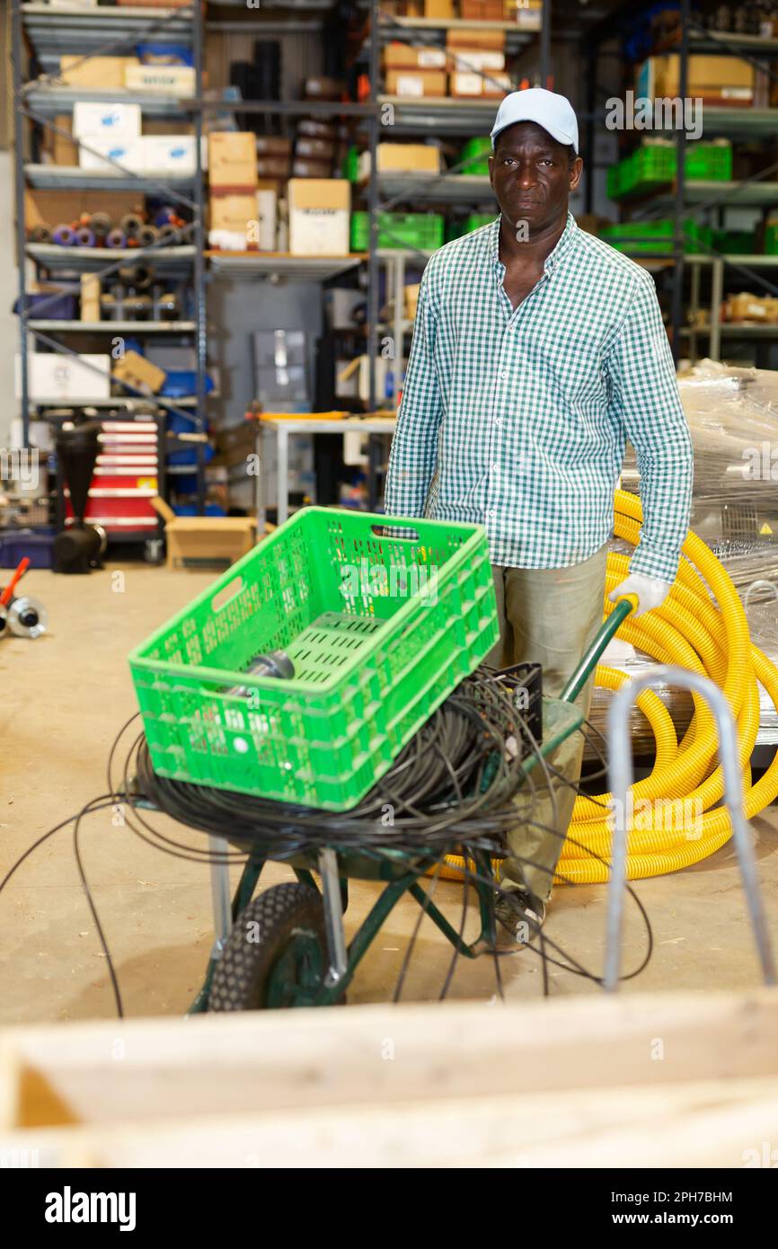 Warehouse worker pushing cart in storage room Stock Photo - Alamy