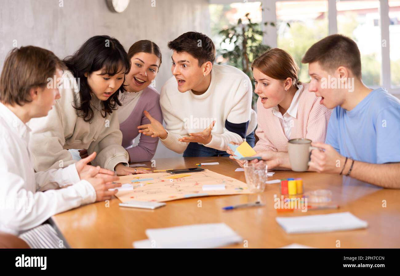 Group of students playing board game around the table Stock Photo - Alamy