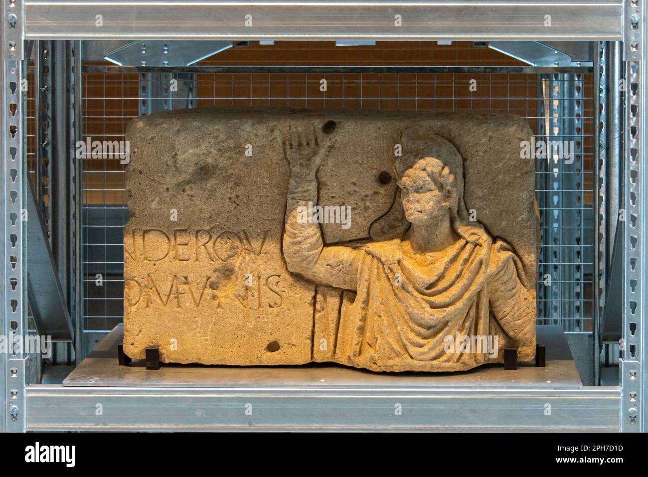 A carved relief stone with a male figure from a Roman tomb on the shelf ...