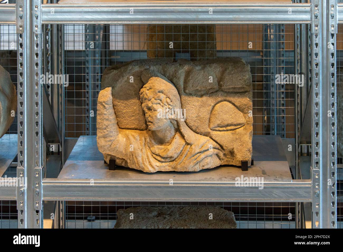 A carved relief stone with a male figure from a Roman tomb on the shelf ...