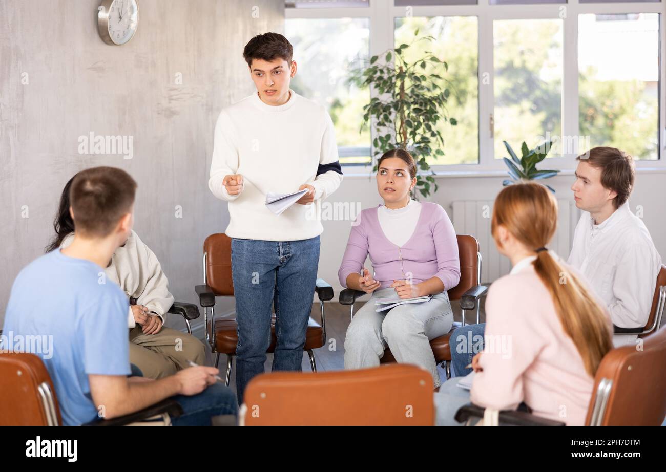 Teenager boy tells an interesting story. Girls and boys listening ...
