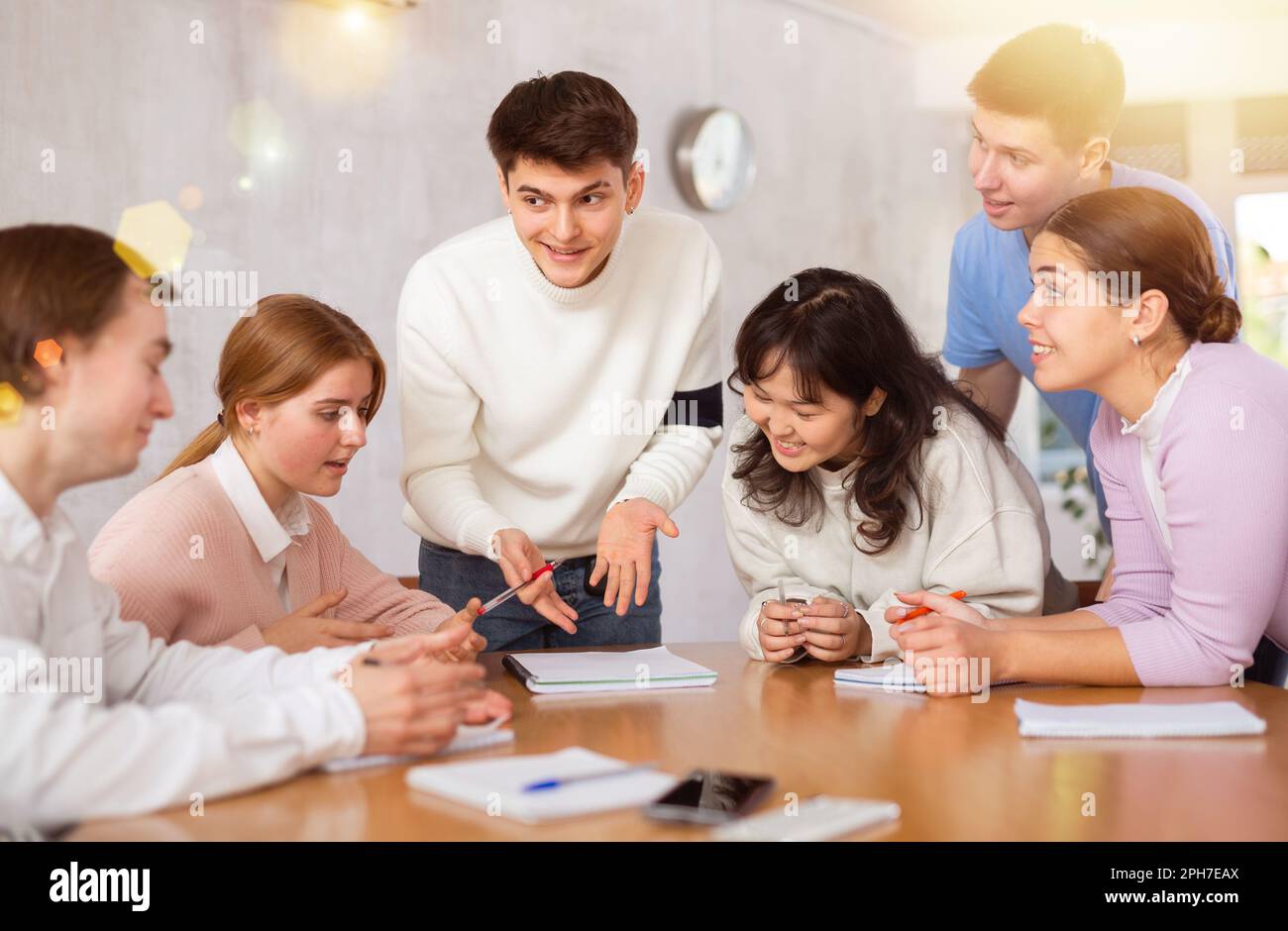 Young teacher discussing his notes with students around the table Stock ...