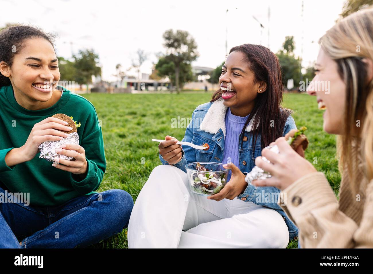 Young group of happy diverse women having lunch at green park campus ...