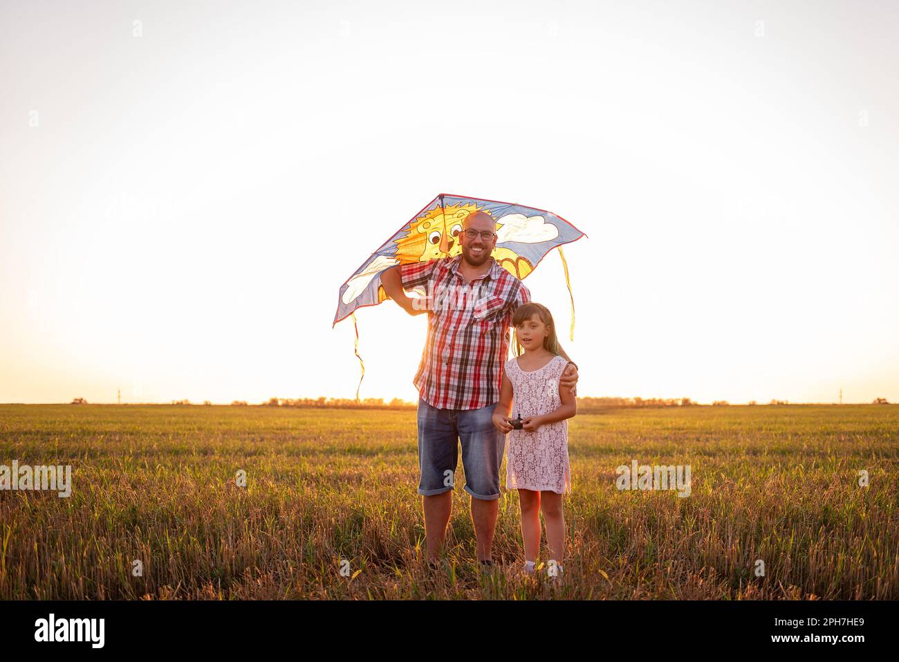 Bald father in glasses runs around the field with daughter putting into ...