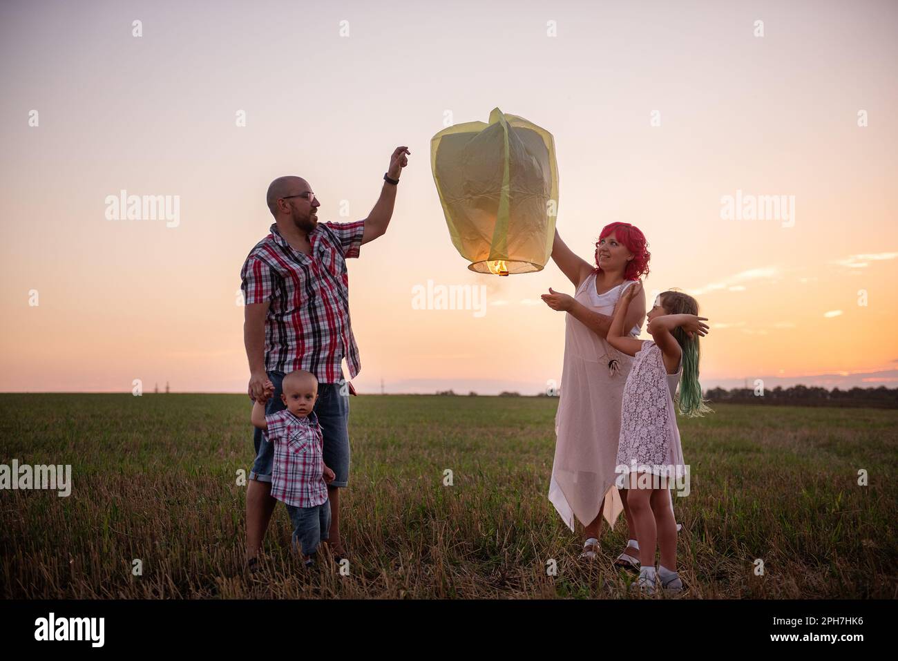 Diversity family launch yellow sky lantern in field at sunset. Mother ...