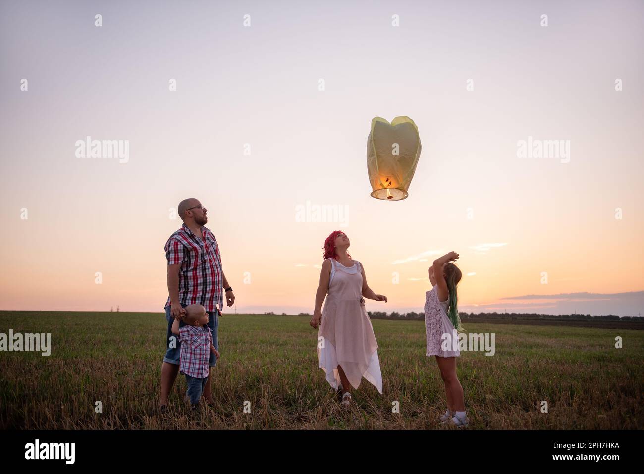 Diversity family launch yellow sky lantern in field at sunset. Mother ...