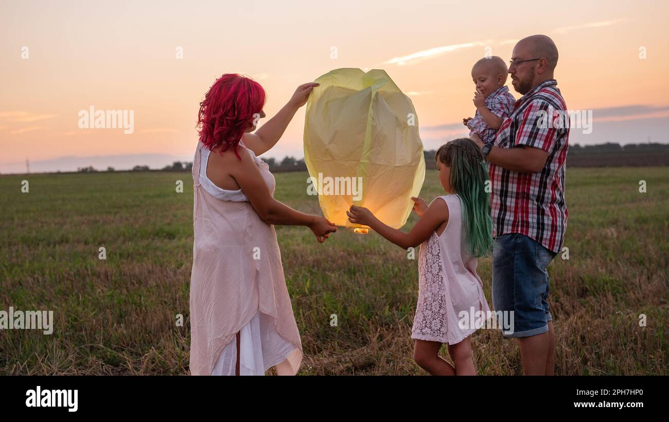 Diversity family launch yellow sky lantern in field at sunset. Mother ...