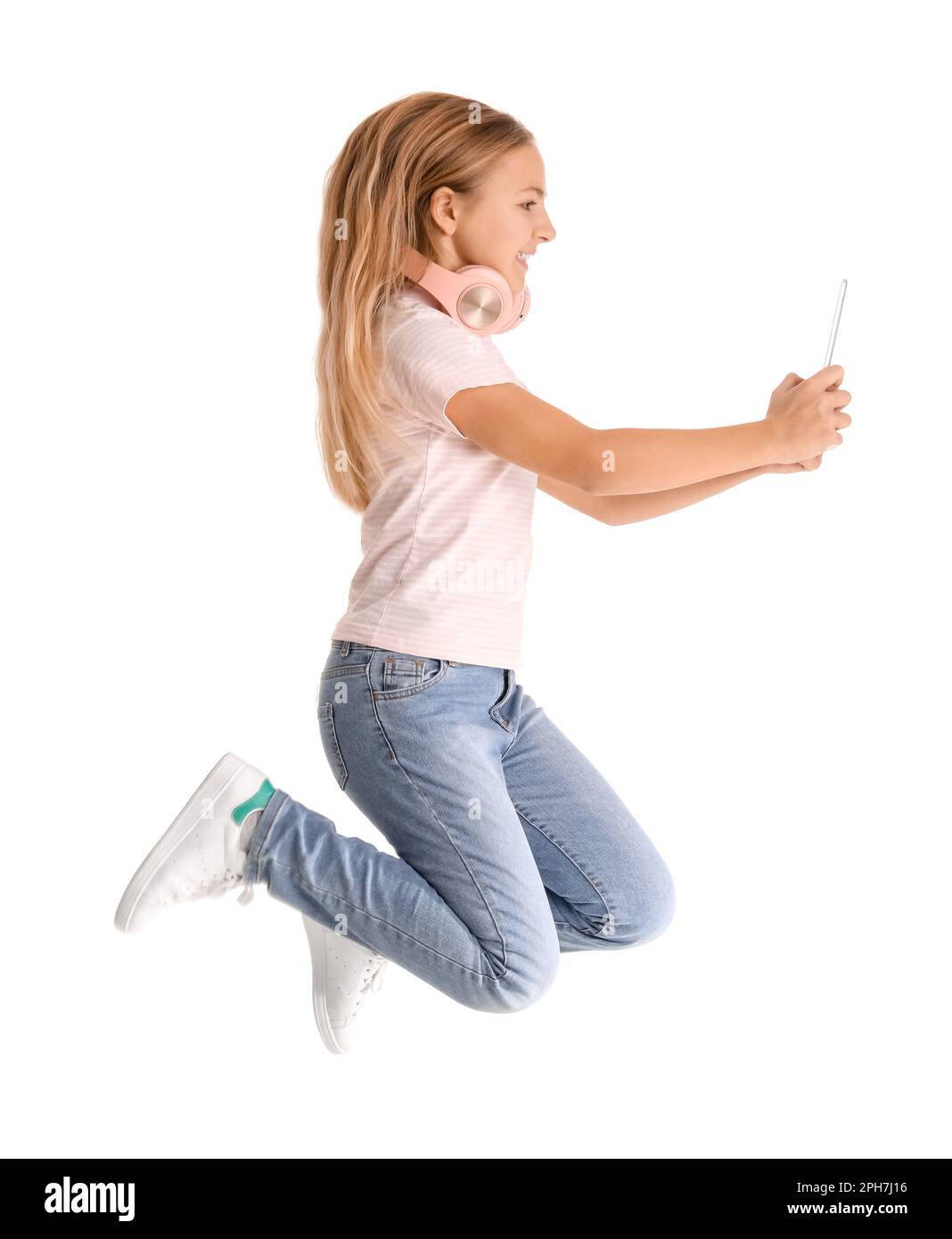Little girl with headphones and tablet computer jumping on white ...