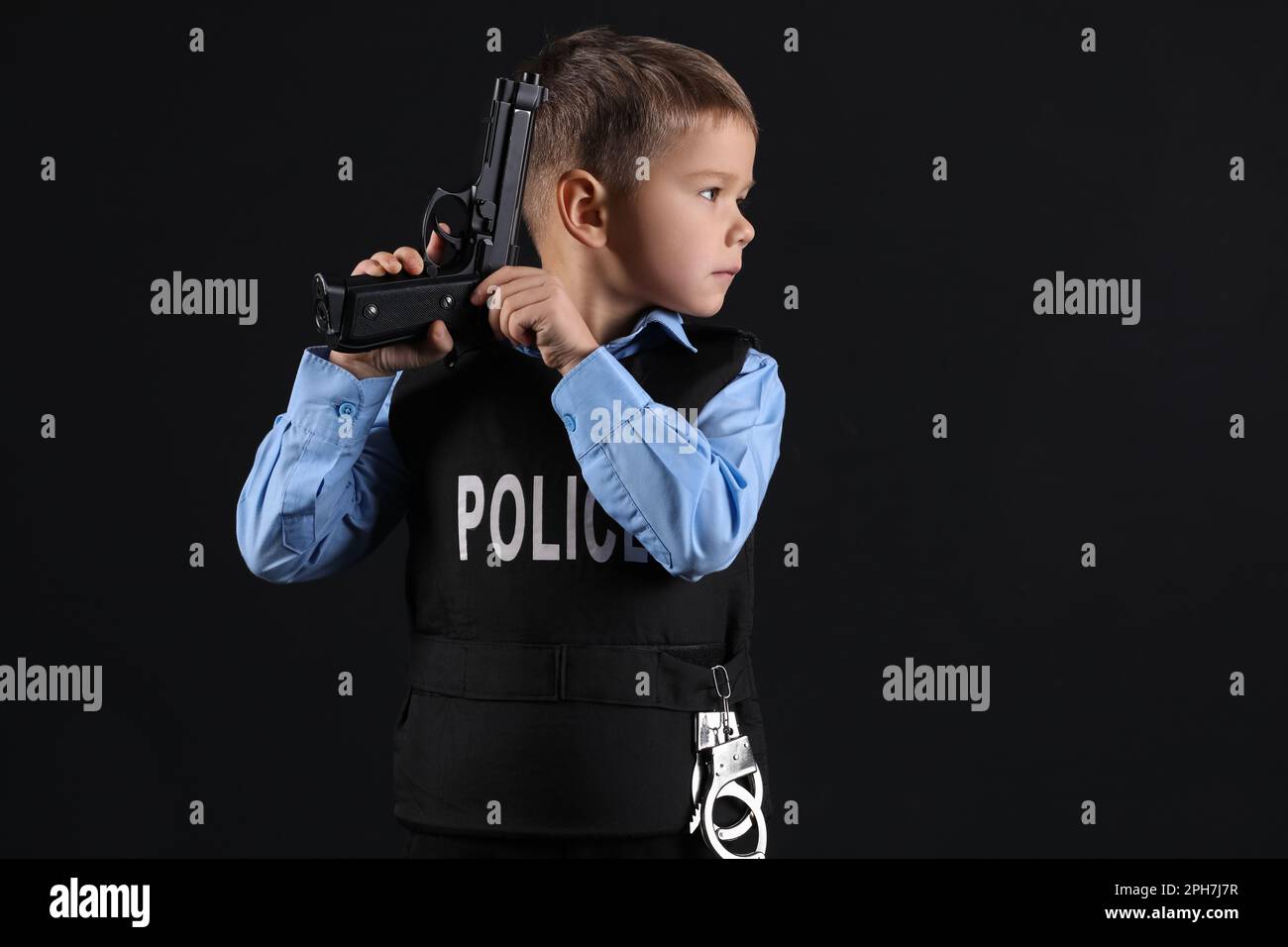 Cute little police officer with gun on black background Stock Photo - Alamy